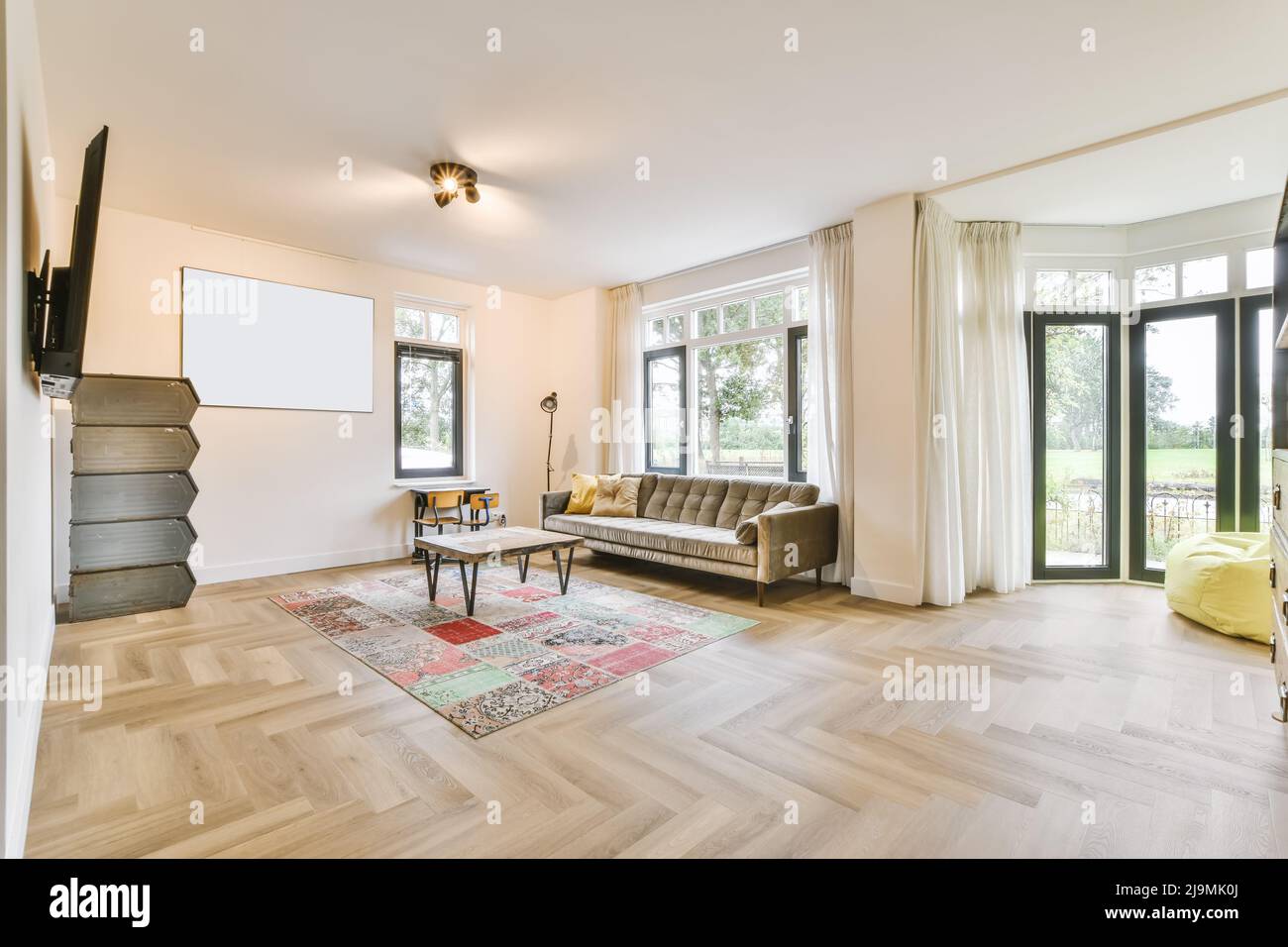 Interior of sunlit living room with sofa and table located near big ...
