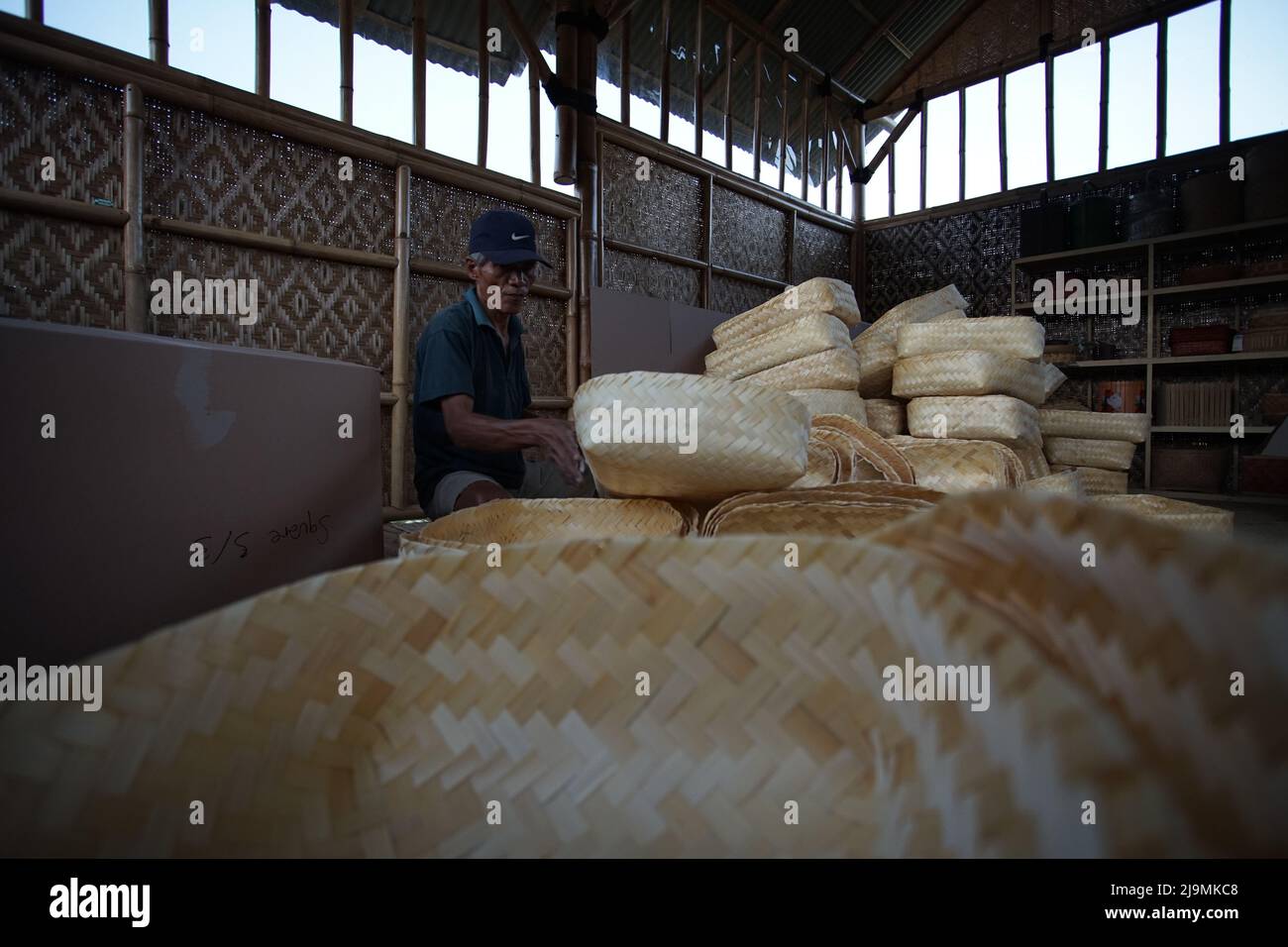 A man prepares traditional bamboo food box called "besek" to packaging ...