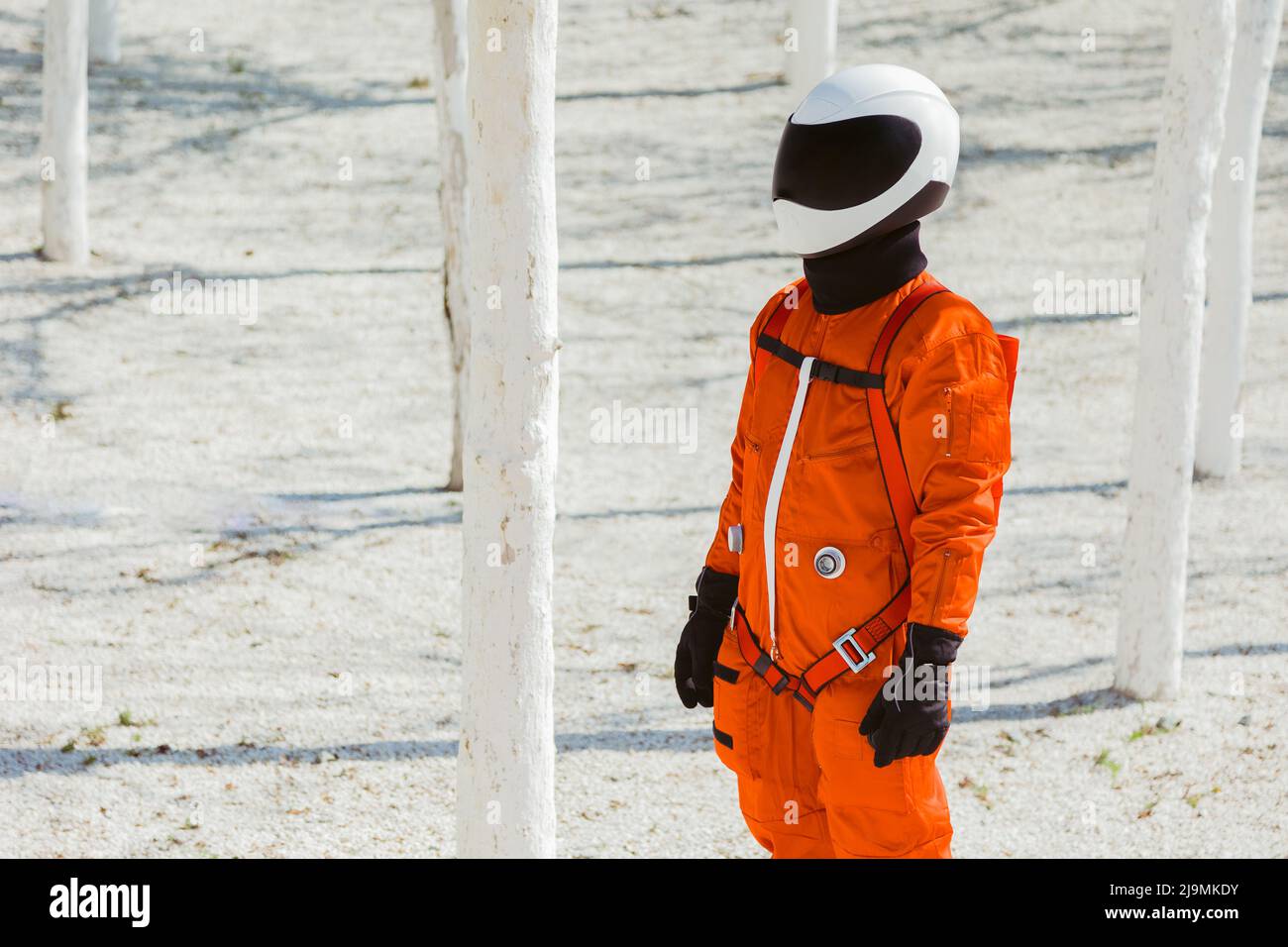Side view of unrecognizable male cosmonaut in bright orange spacesuit ...