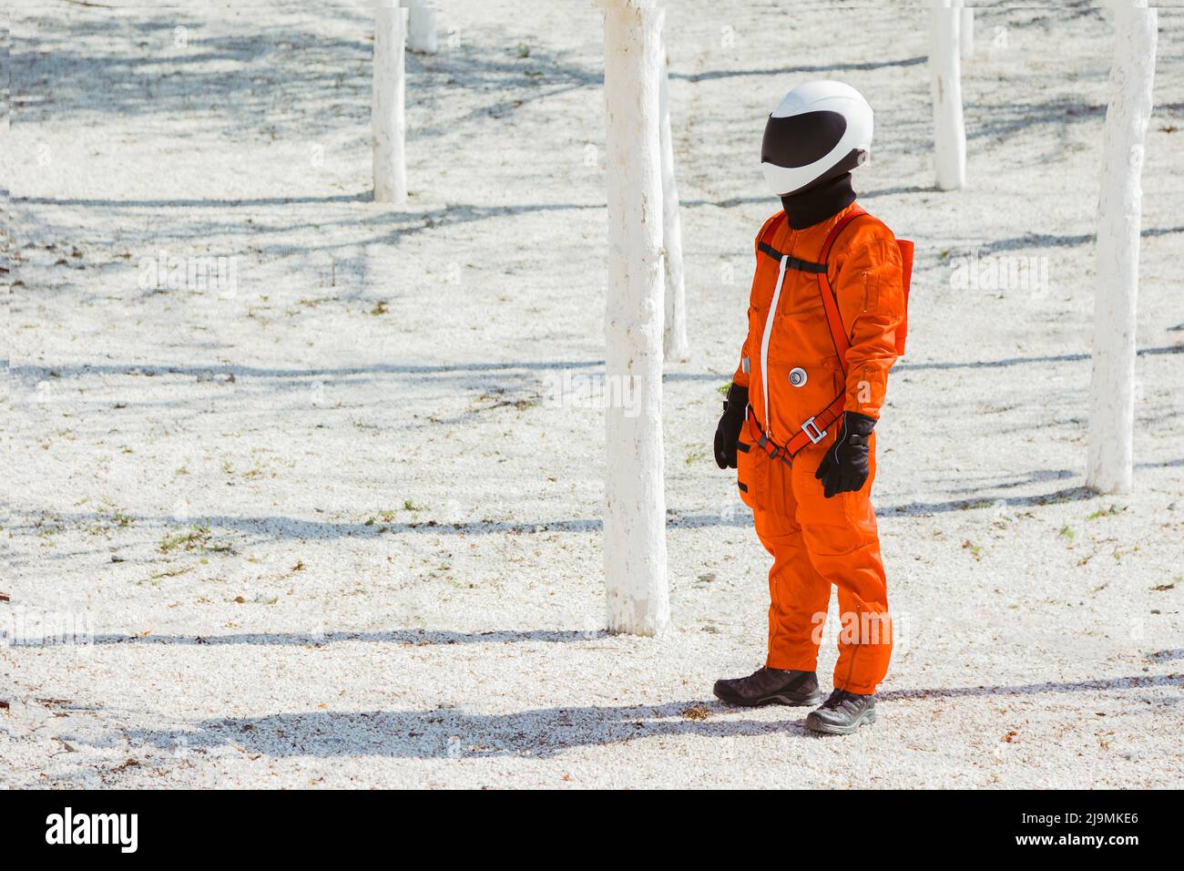 Side view of unrecognizable male cosmonaut in bright orange spacesuit ...