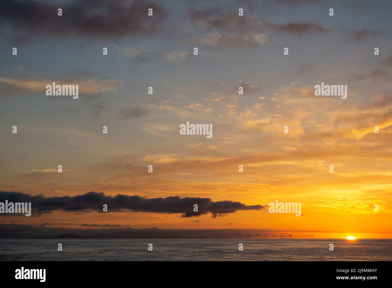 Sunset over the Pacific Ocean with clouds in shadow and fading yellow ...