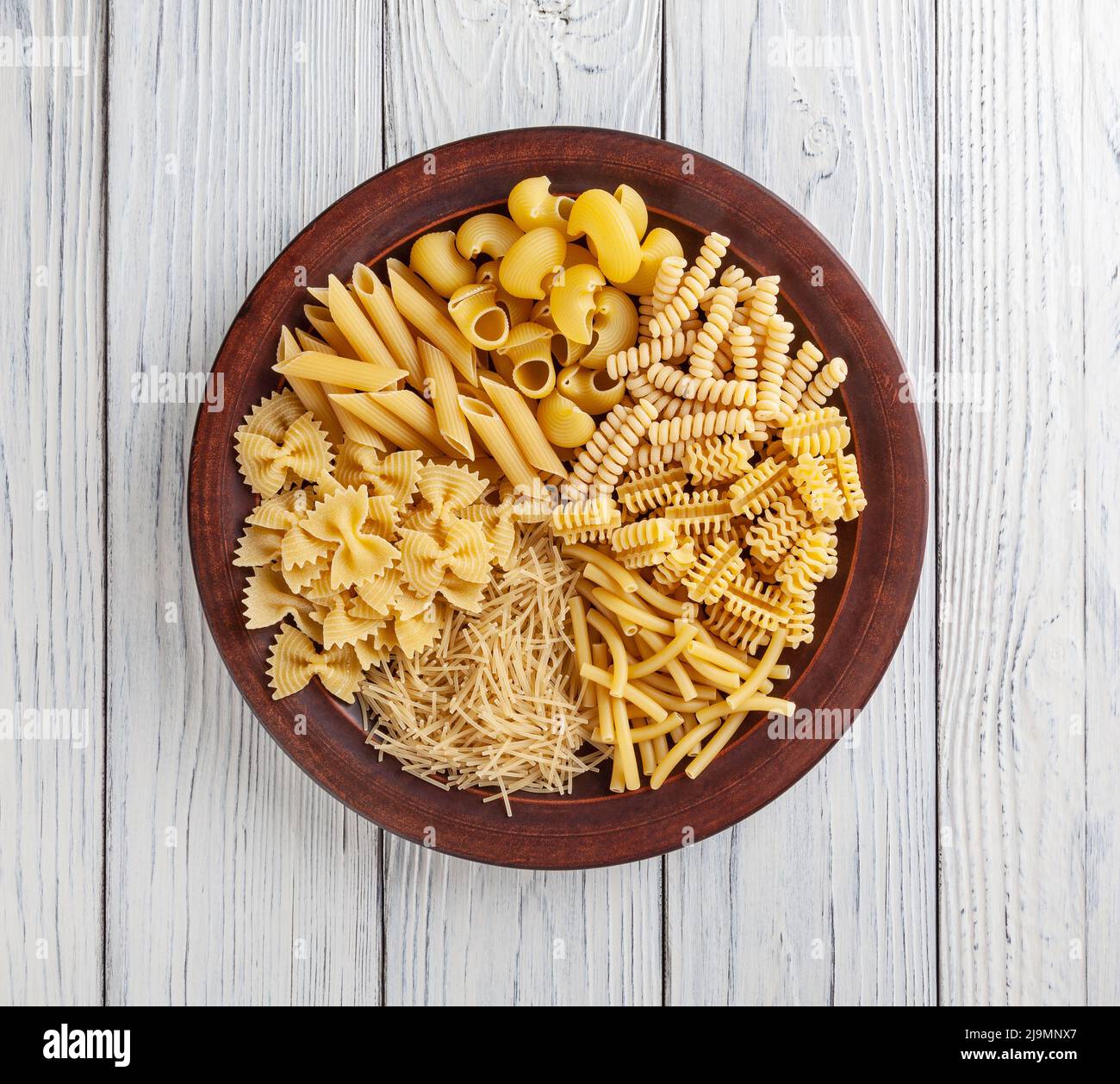 Different types and shapes of Italian pasta in ceramic plate on white ...