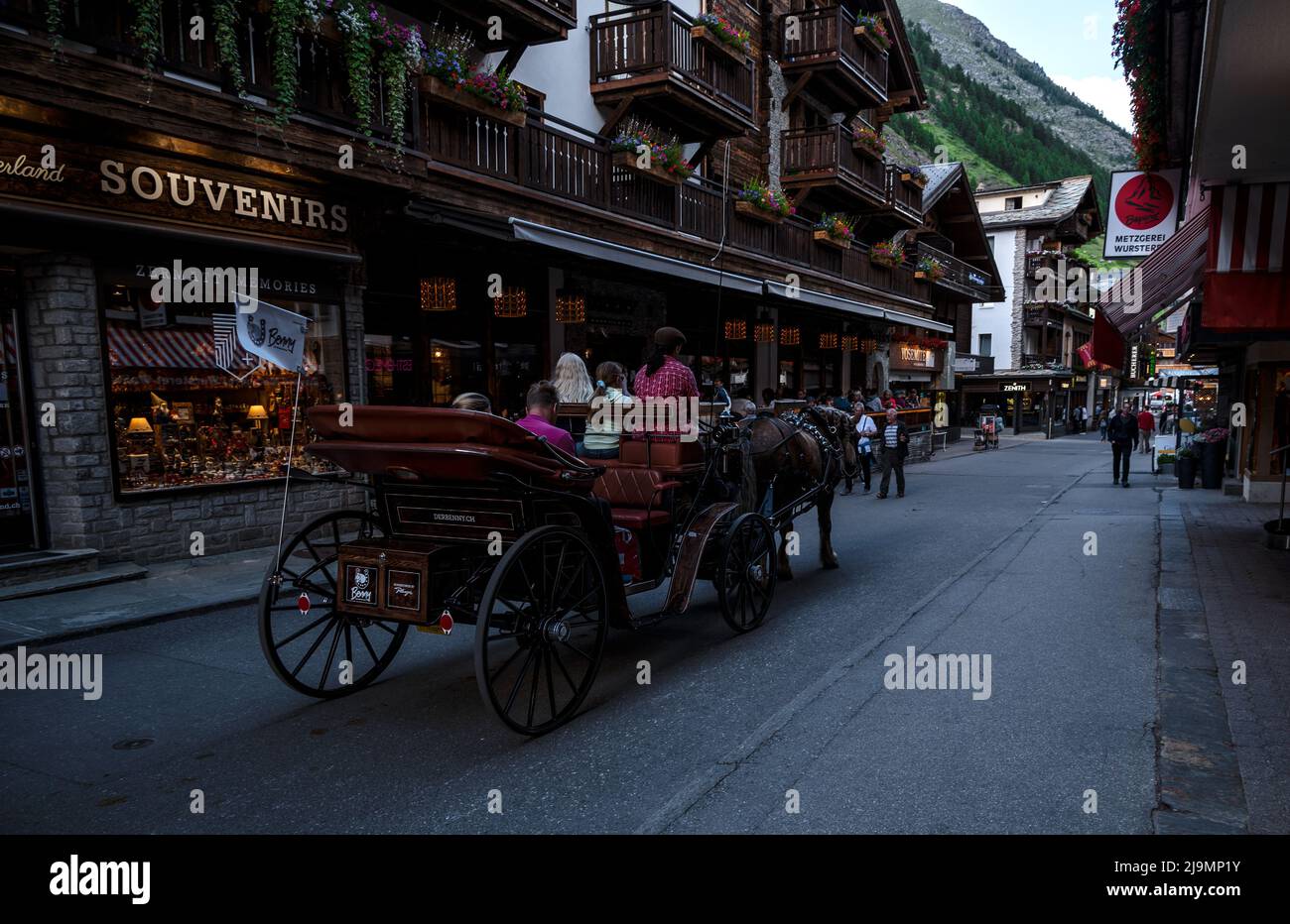 Horse coach carrying tourists on the main shopping street of Zermatt ...