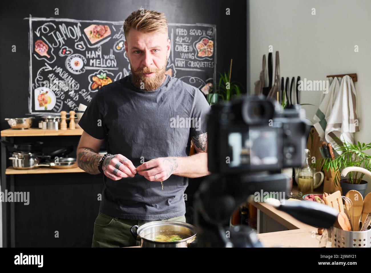 Stylish tattooed Caucasian man with beard on face filming content for ...