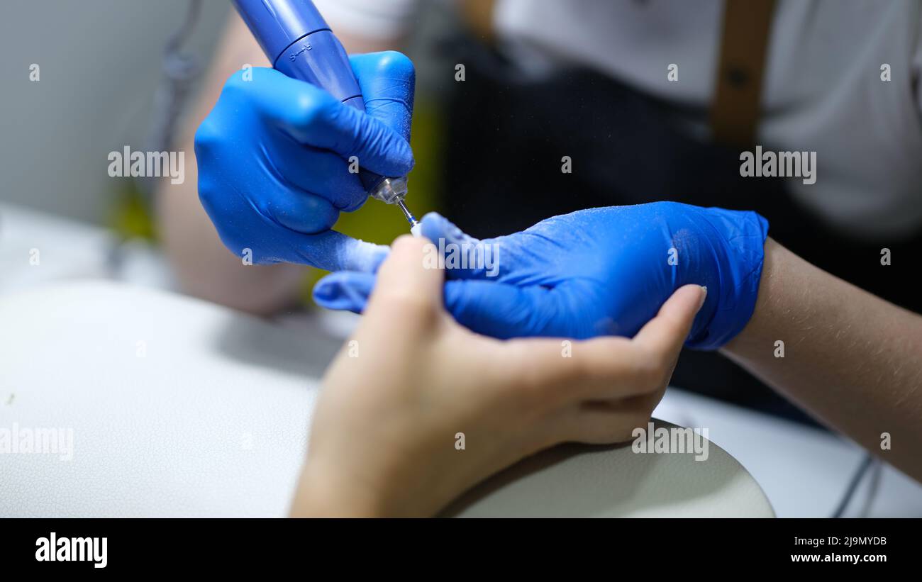 Manicurist uses electric manicure machine to remove nail polish from ...