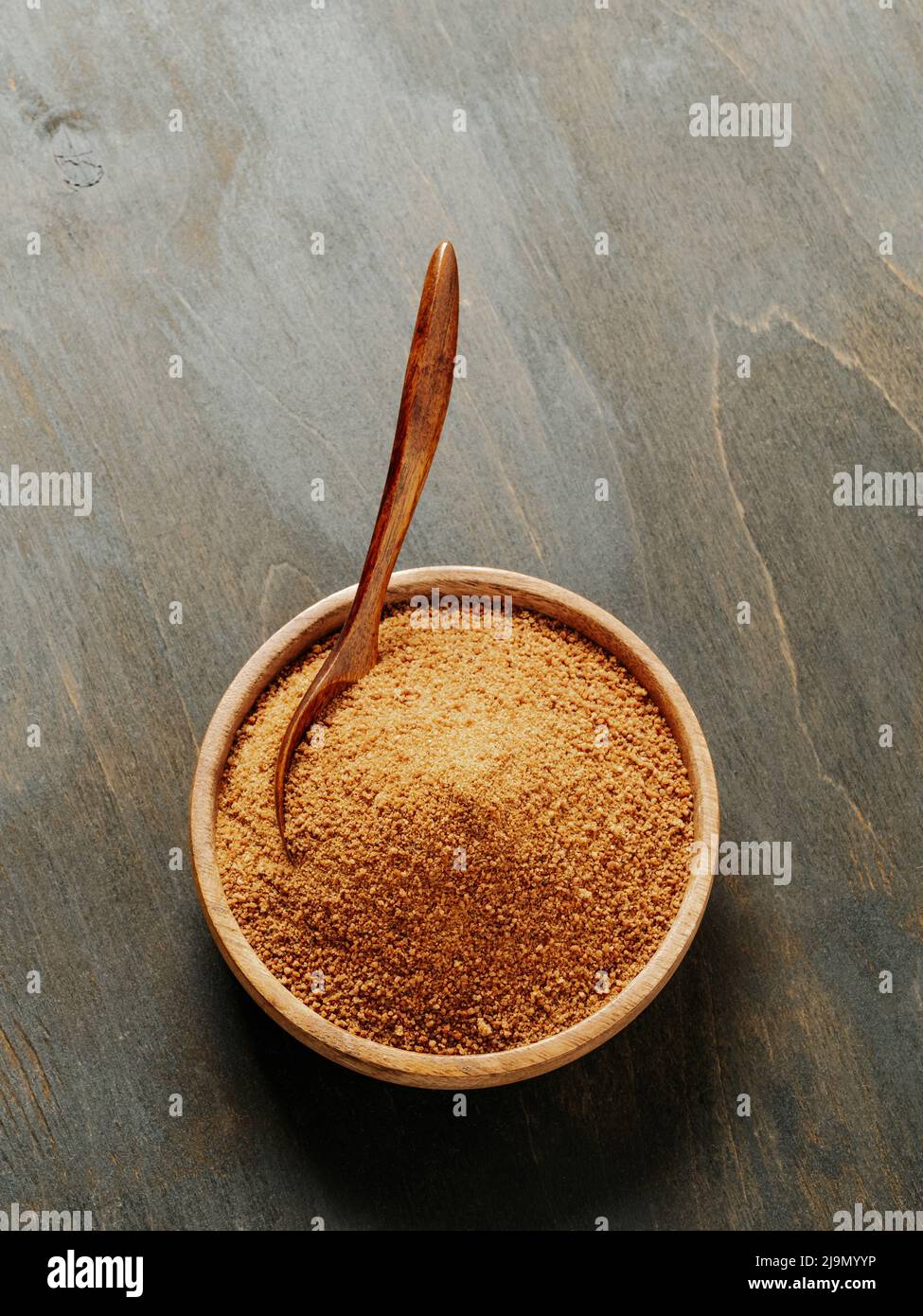 Bowl and spoon of coconut brown sugar on wooden background.Top view of ...