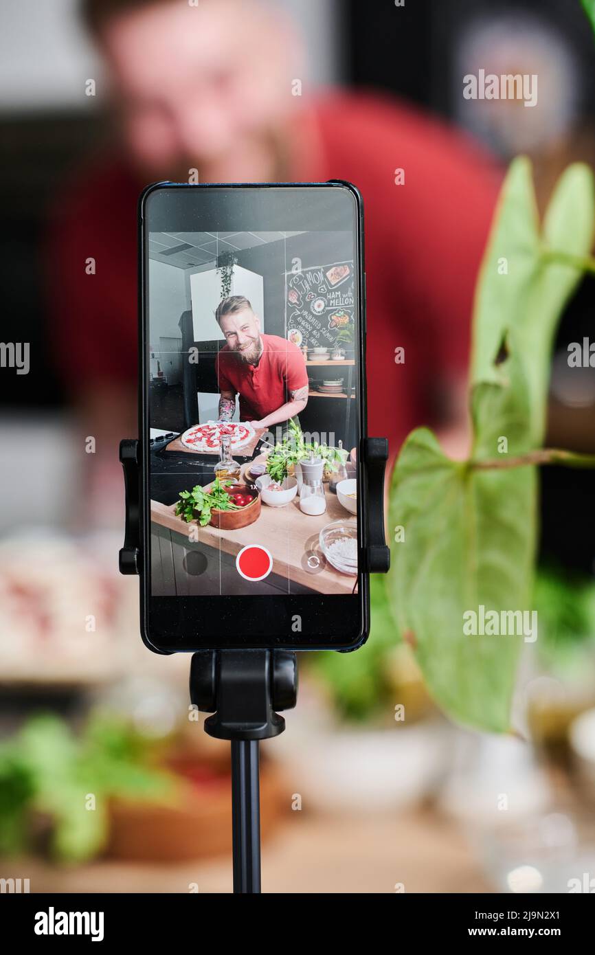 Selective close-up shot of modern male food blogger filming pizza ...