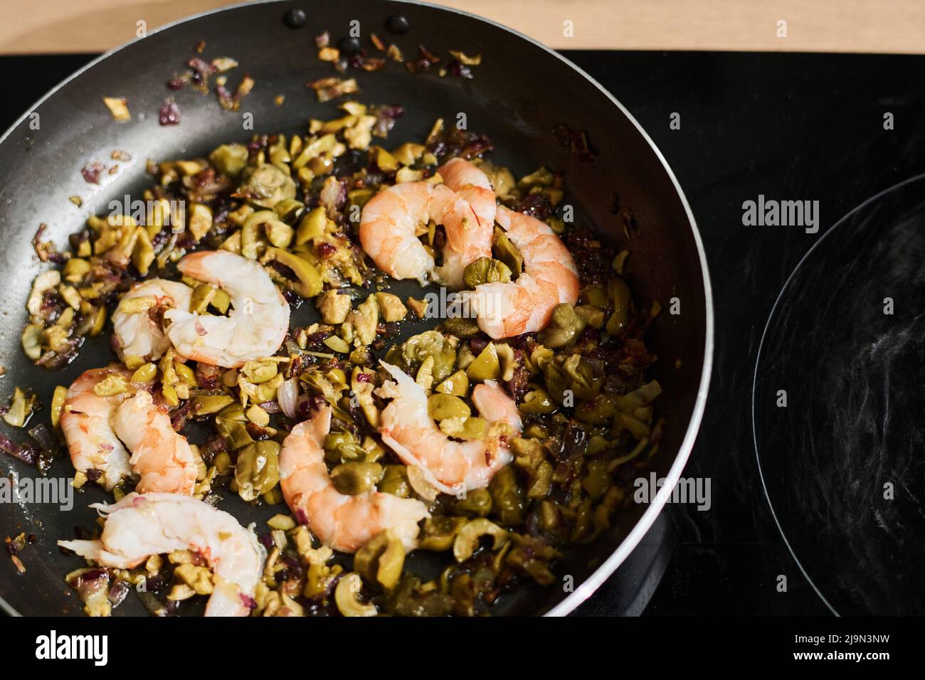 High angle close-up of shrimps with chopped olives and red onion in ...