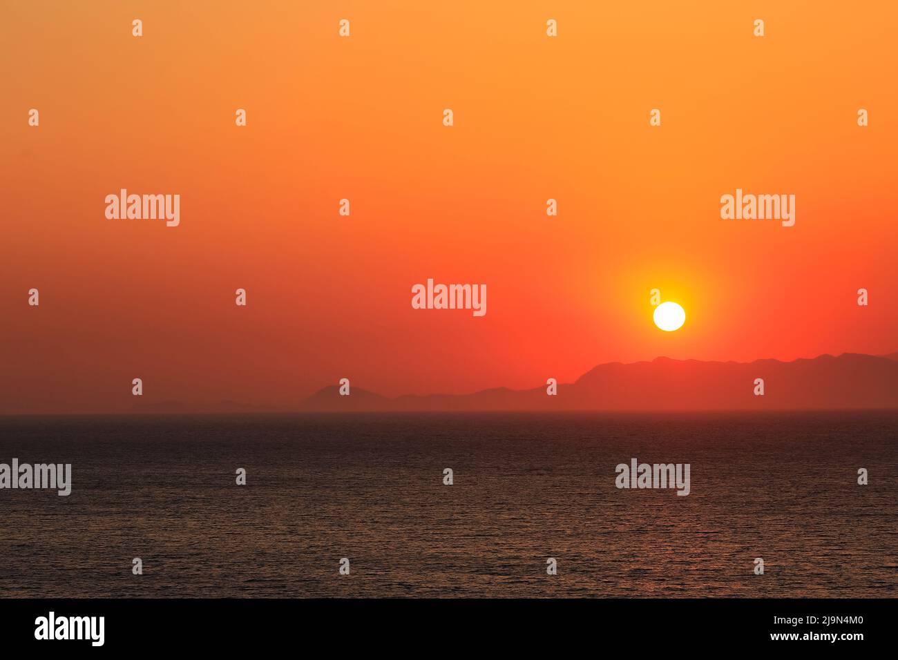Colorful sunset at the town Rhodos with view of the foggy silhouette of ...