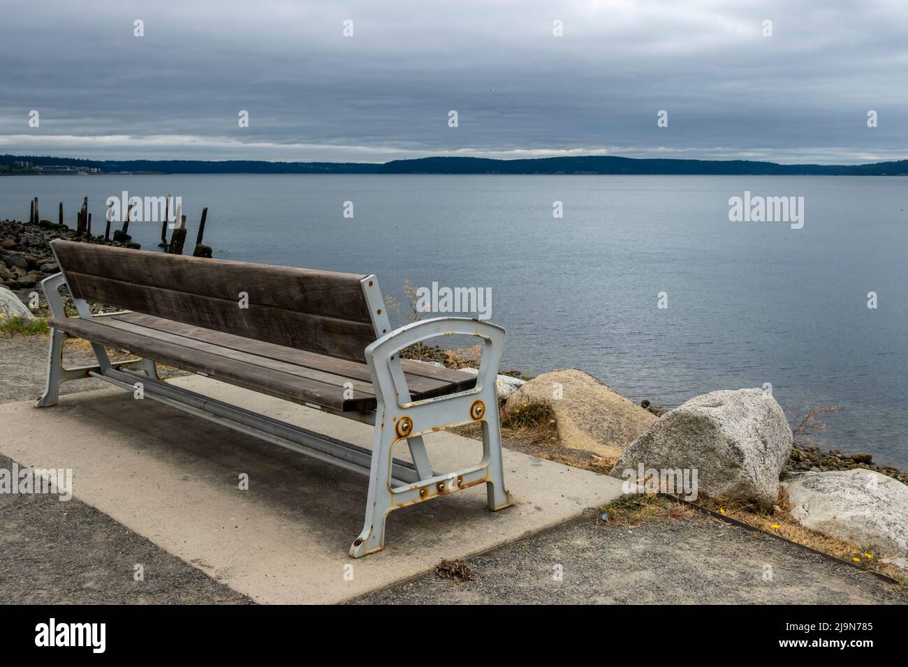 Angled view behind a wooden park bench with the Tacoma city skyline off ...