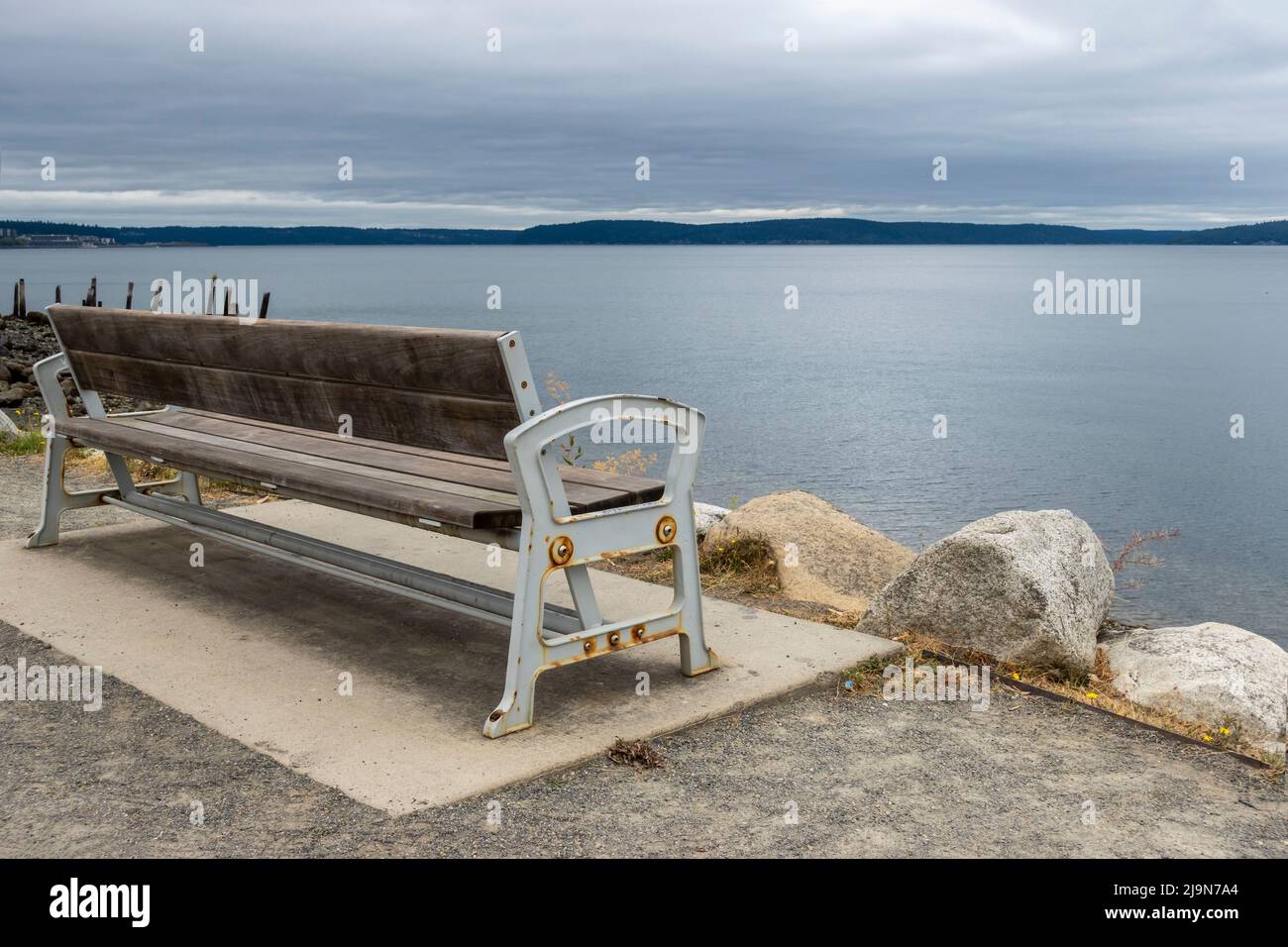 Angled view behind a wooden park bench with the Tacoma city skyline off ...