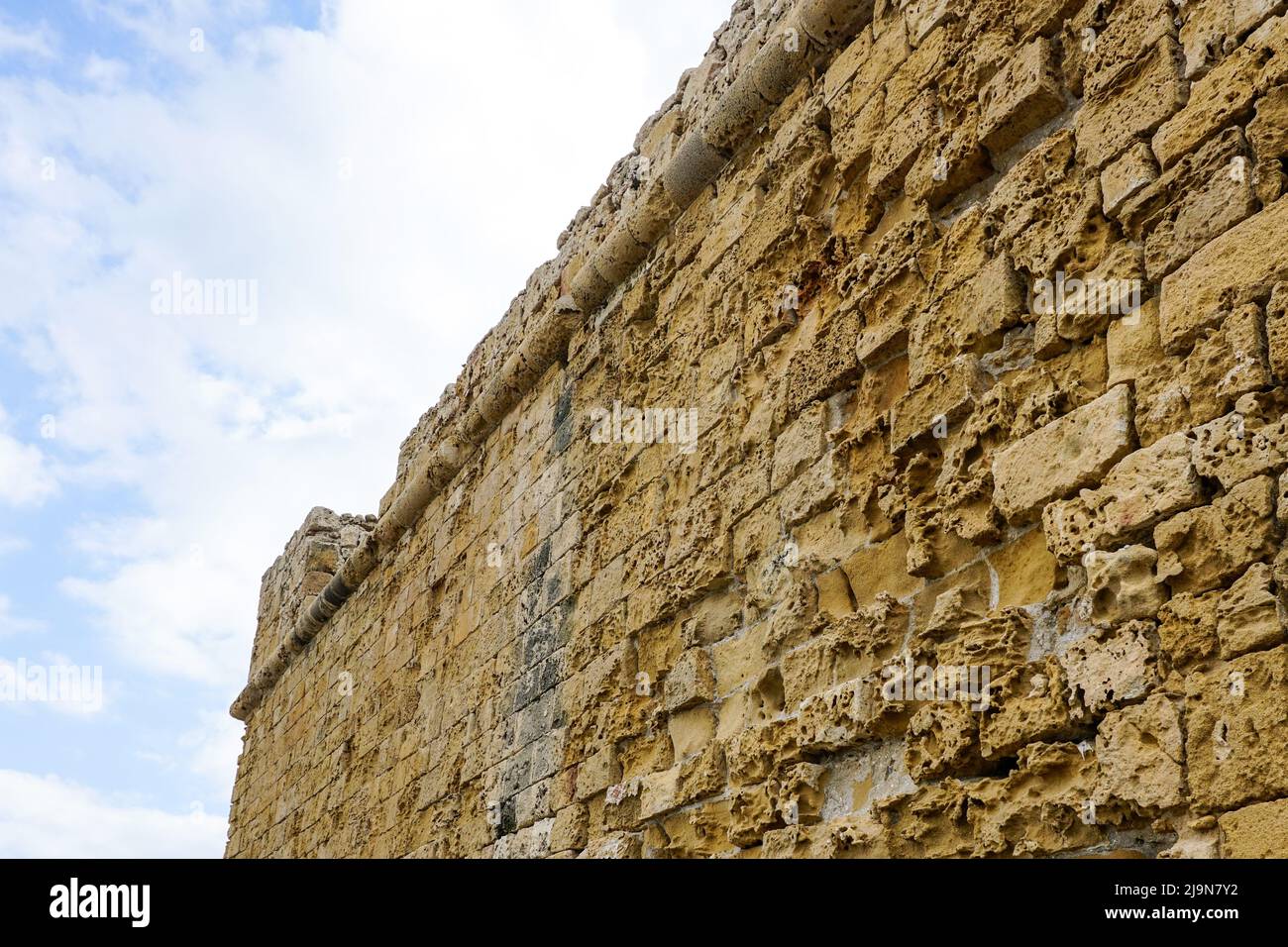 a fragment of an ancient fortress sandstone wall with crumbling and ...