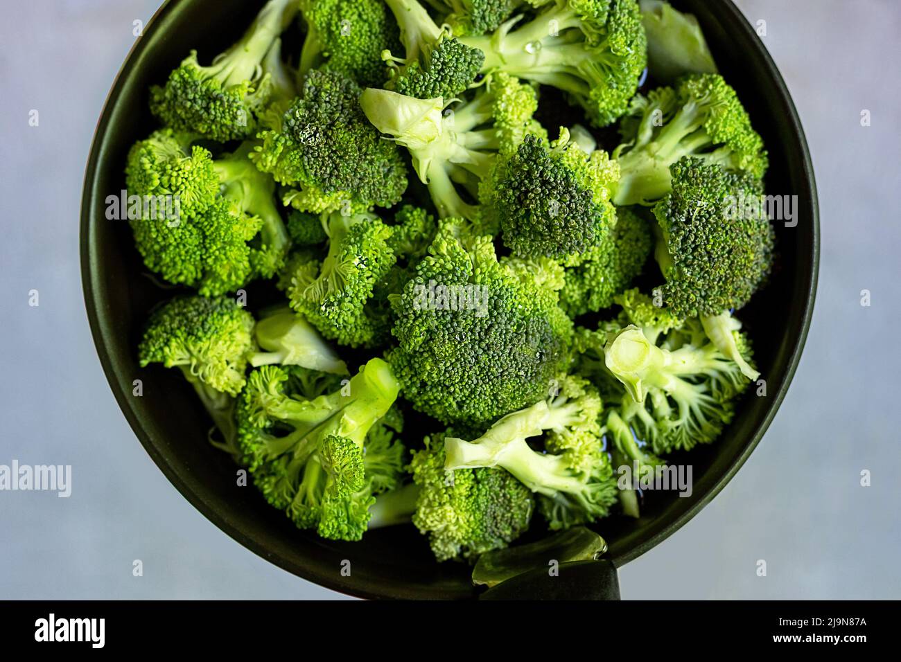 Bright green inflorescences of fresh broccoli in a frying pan in water ...