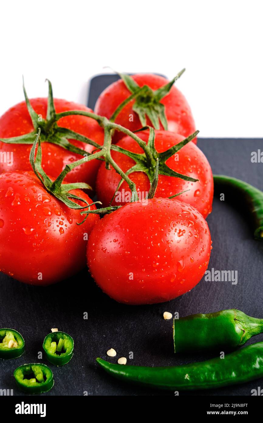 Tomatoes and pod of hot pepper on slate cutting board, isolated white ...