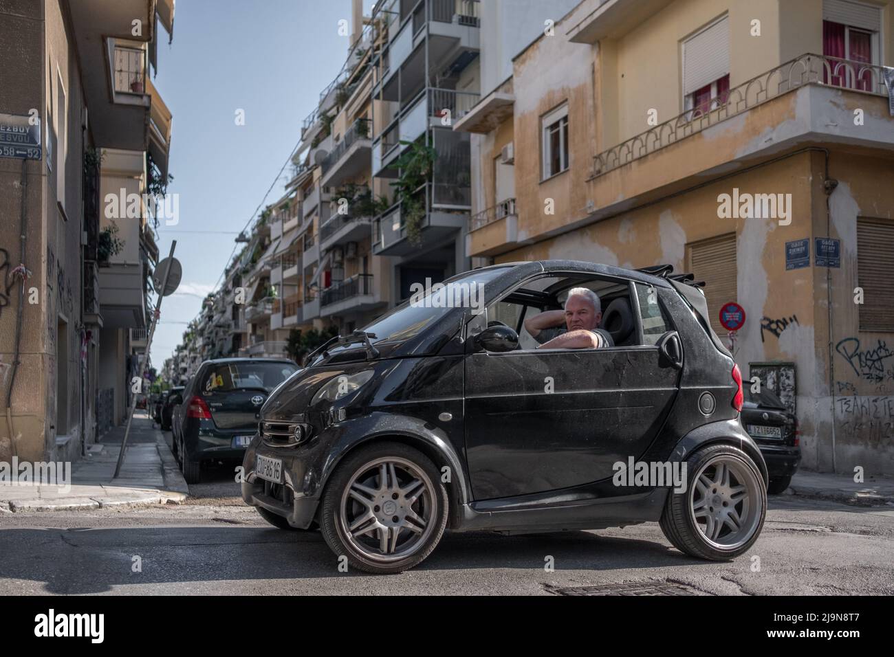 Driver with elbow on window of his Smart car in Athens Stock Photo - Alamy