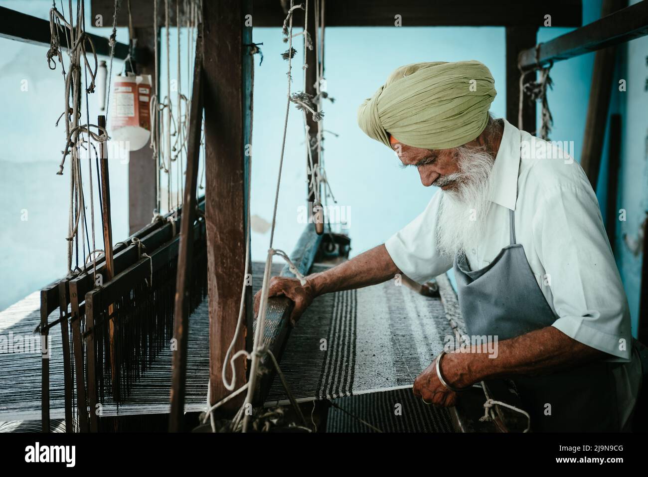An old weaver working the handloom at a traditional village in Punjab ...