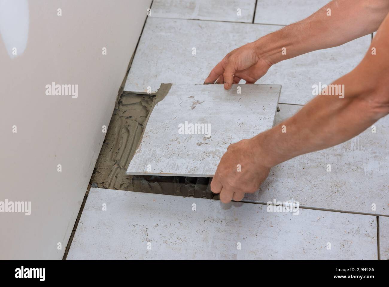 Tiler placing ceramic floor tile in position over adhesive Stock Photo ...