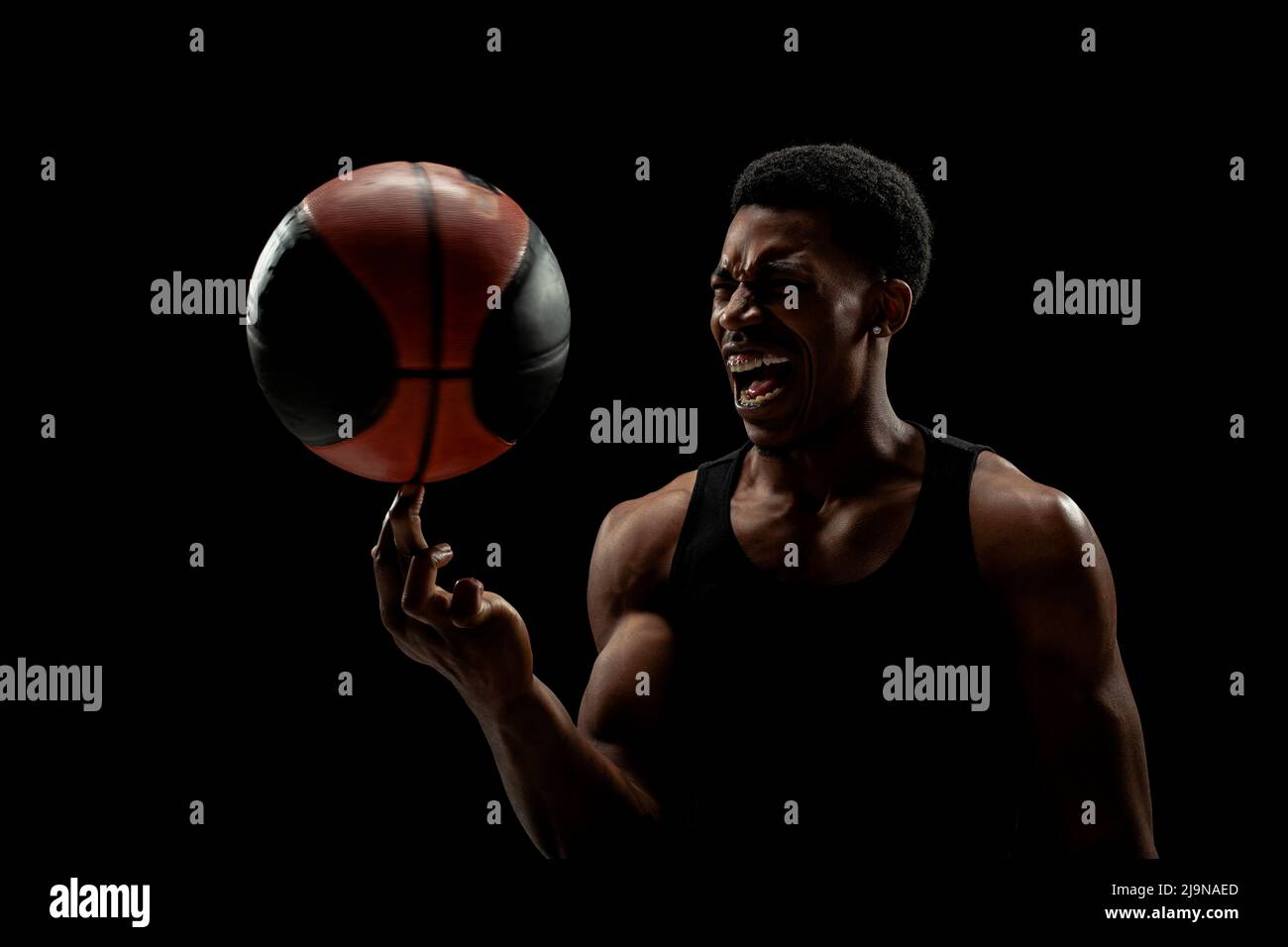 Basketball player spinning a ball against black background. Screaming ...