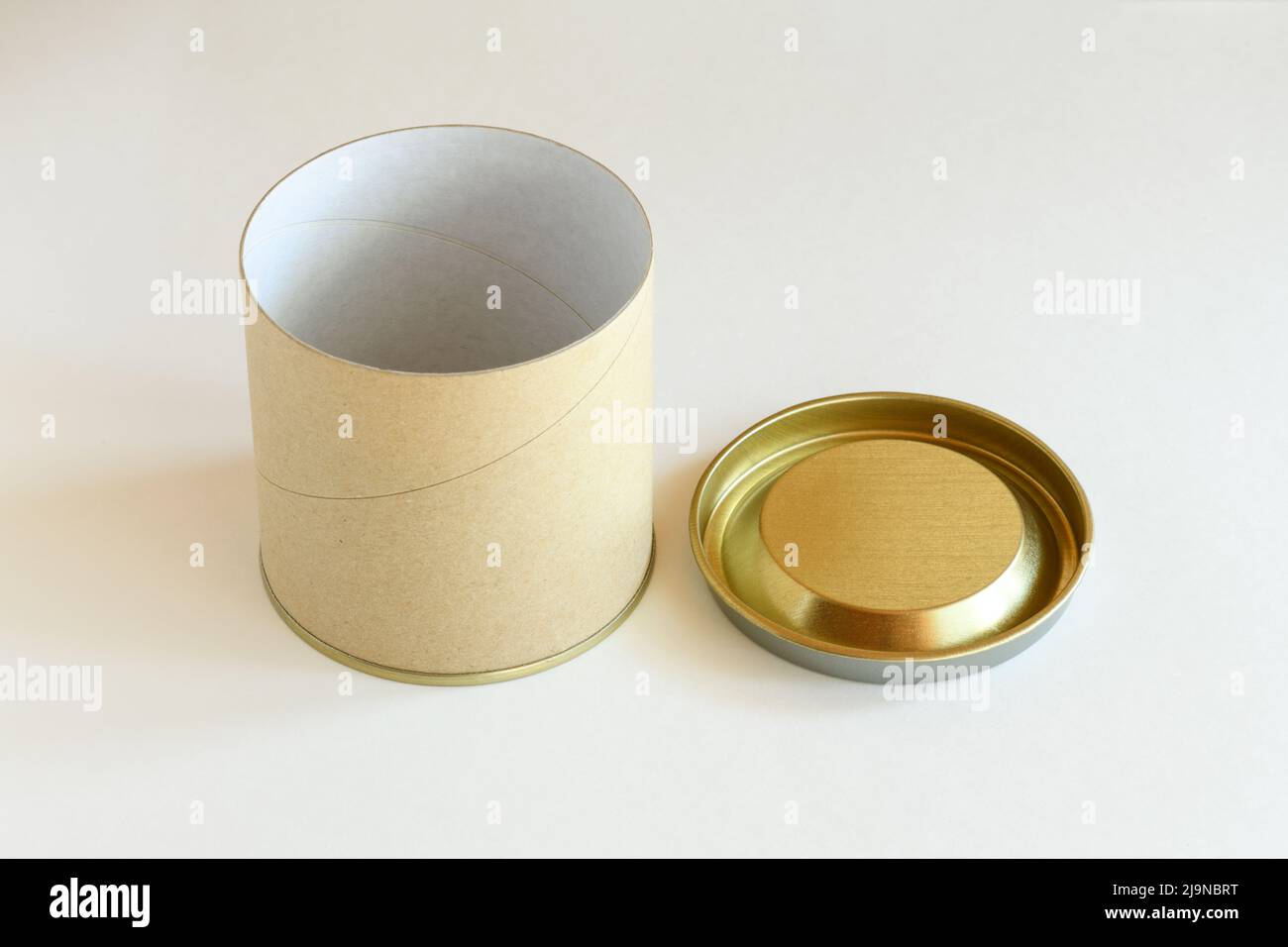 Opened short cardboard cylinder tube with metal lid on white background ...