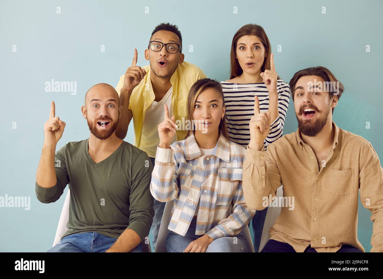 Group of multiracial young people having ideas pointing index fingers ...