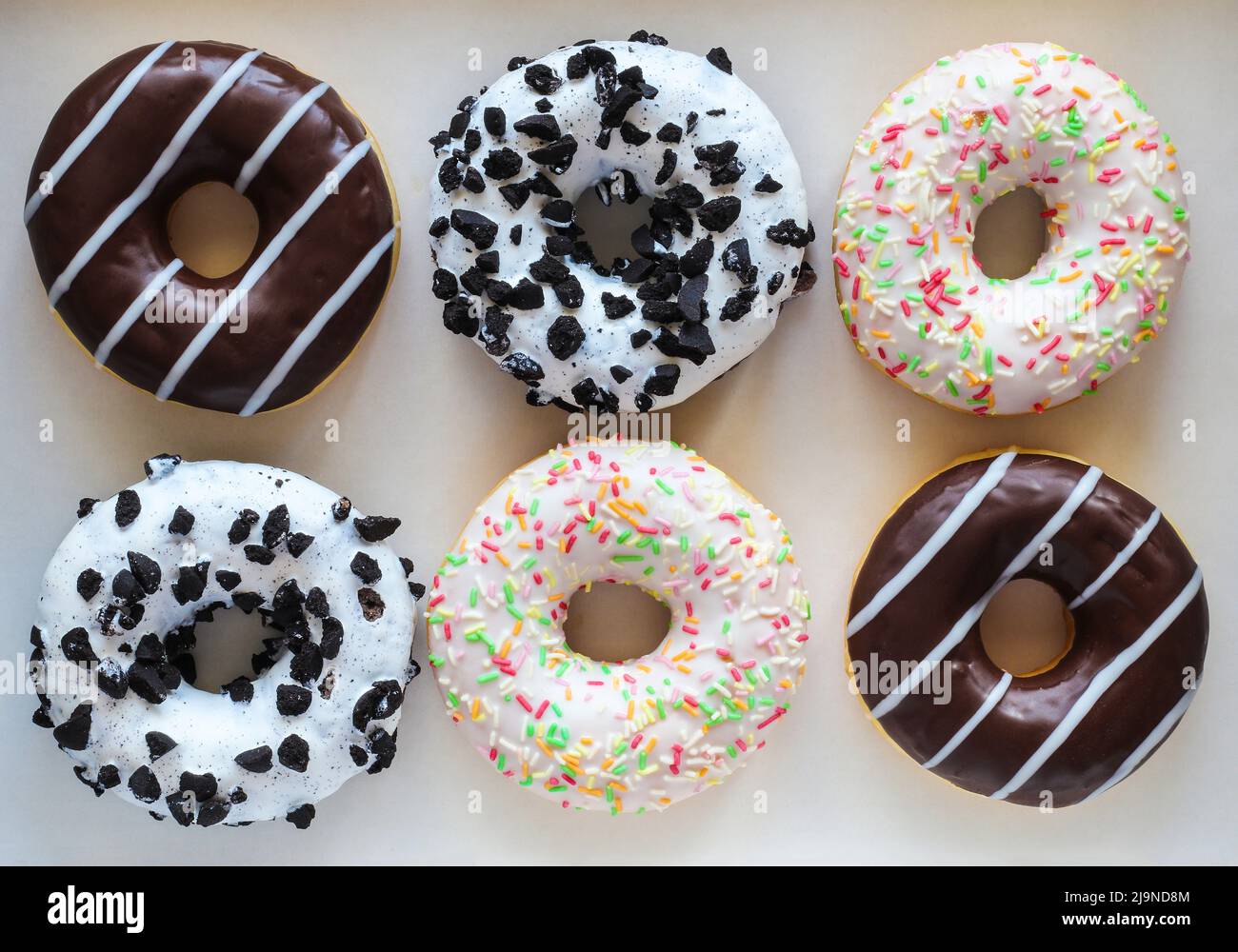 Flat lay image of six ring donuts with white glaze and colourful ...
