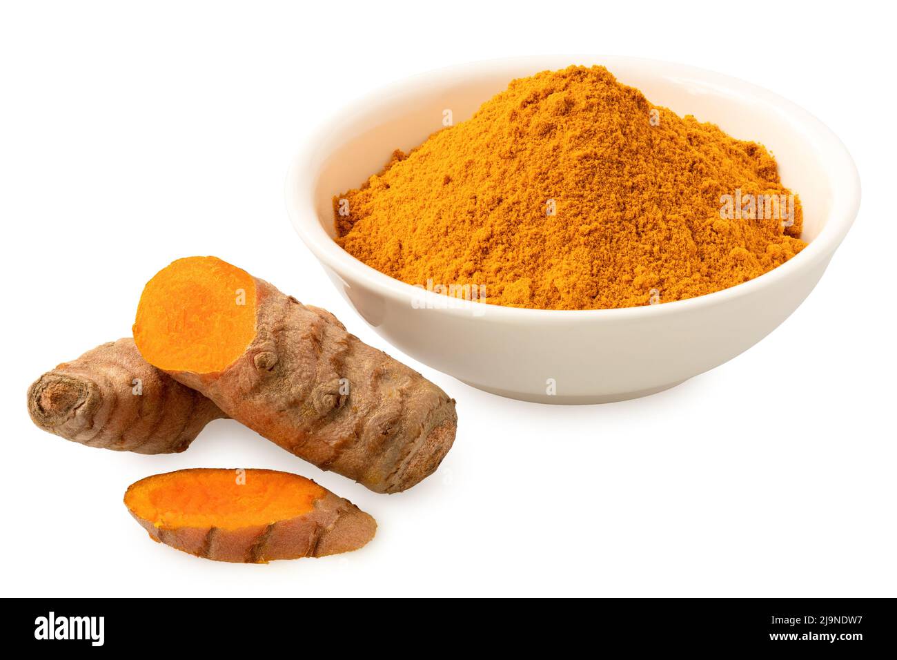 Ground turmeric in white ceramic bowl next to sliced turmeric root ...