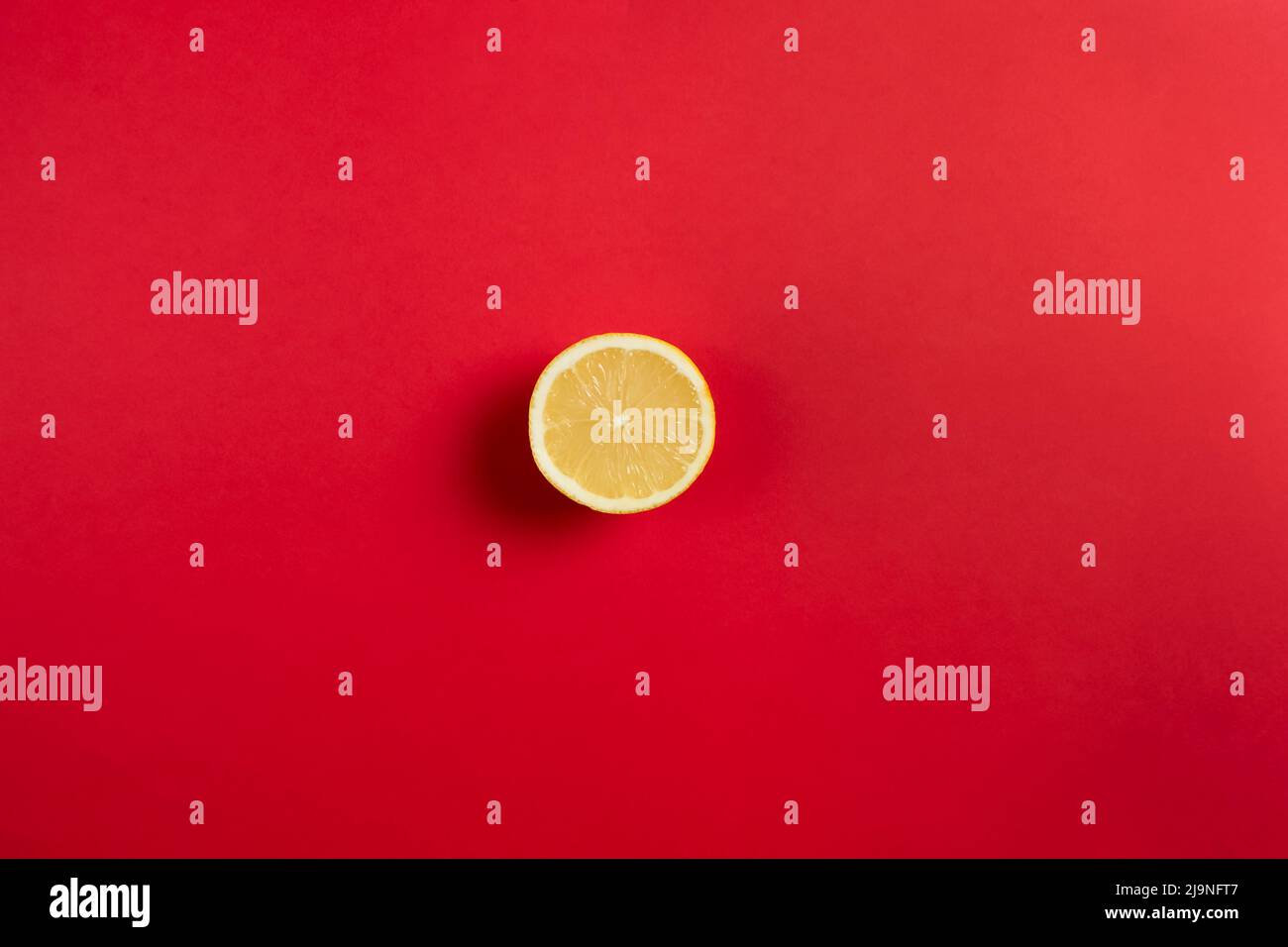 Bright red background with half a lemon in the center of the image ...
