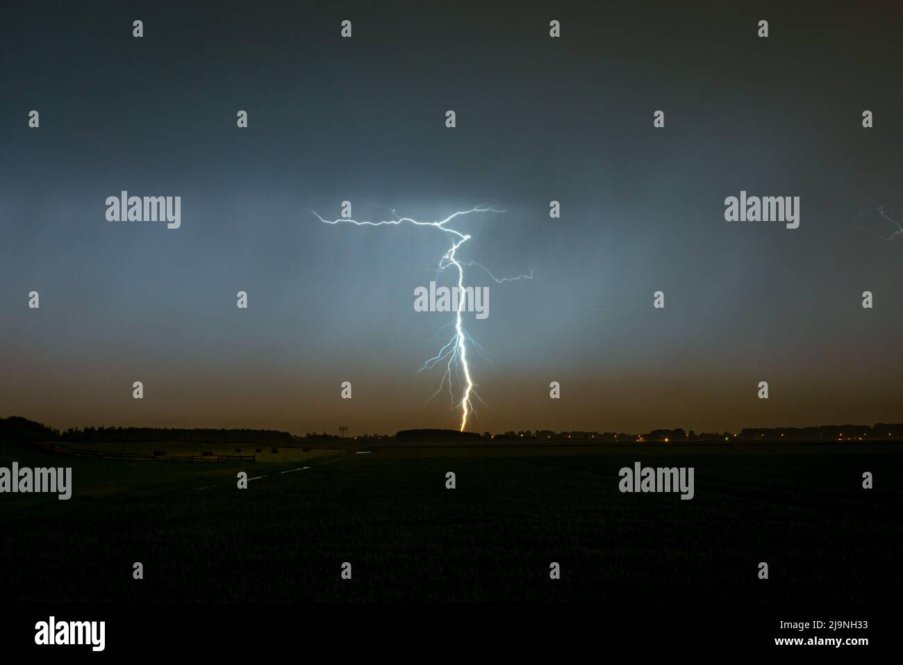 Lightning hits the ground at dusk Stock Photo - Alamy