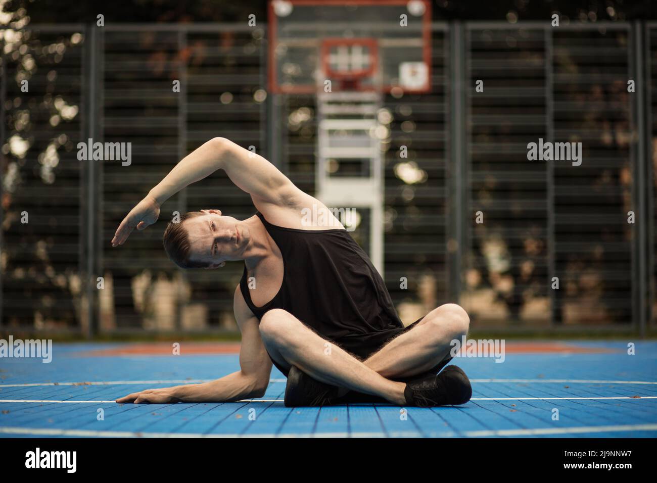 Happy fitness sporty man in black sportswear stretching his arms and ...