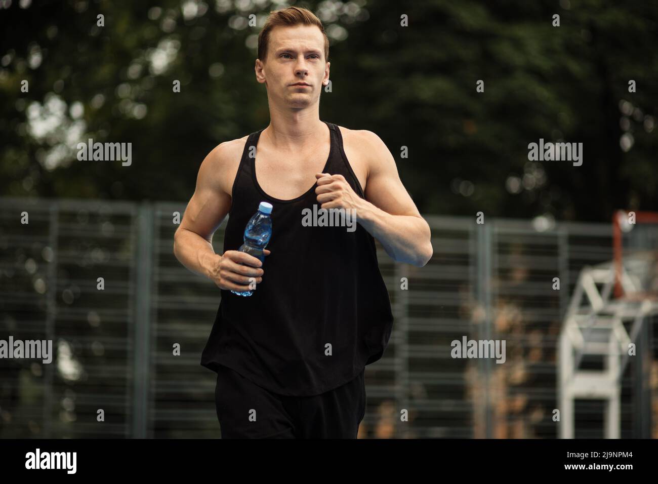 Happy muscular man dressed in sport clothes jogging during morning time ...