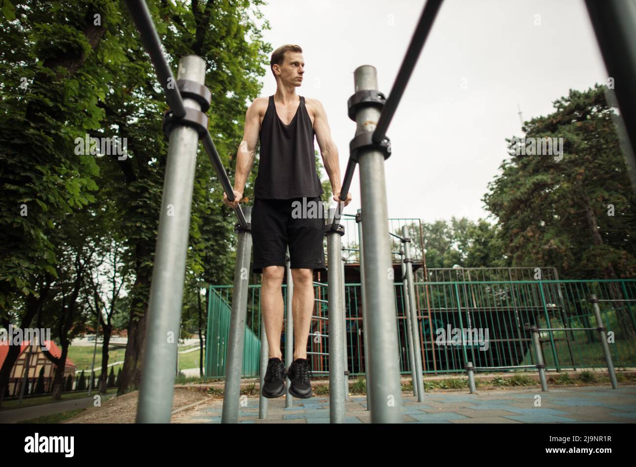 Young caucasian sporty muscular fit man doing triceps dips on parallel ...