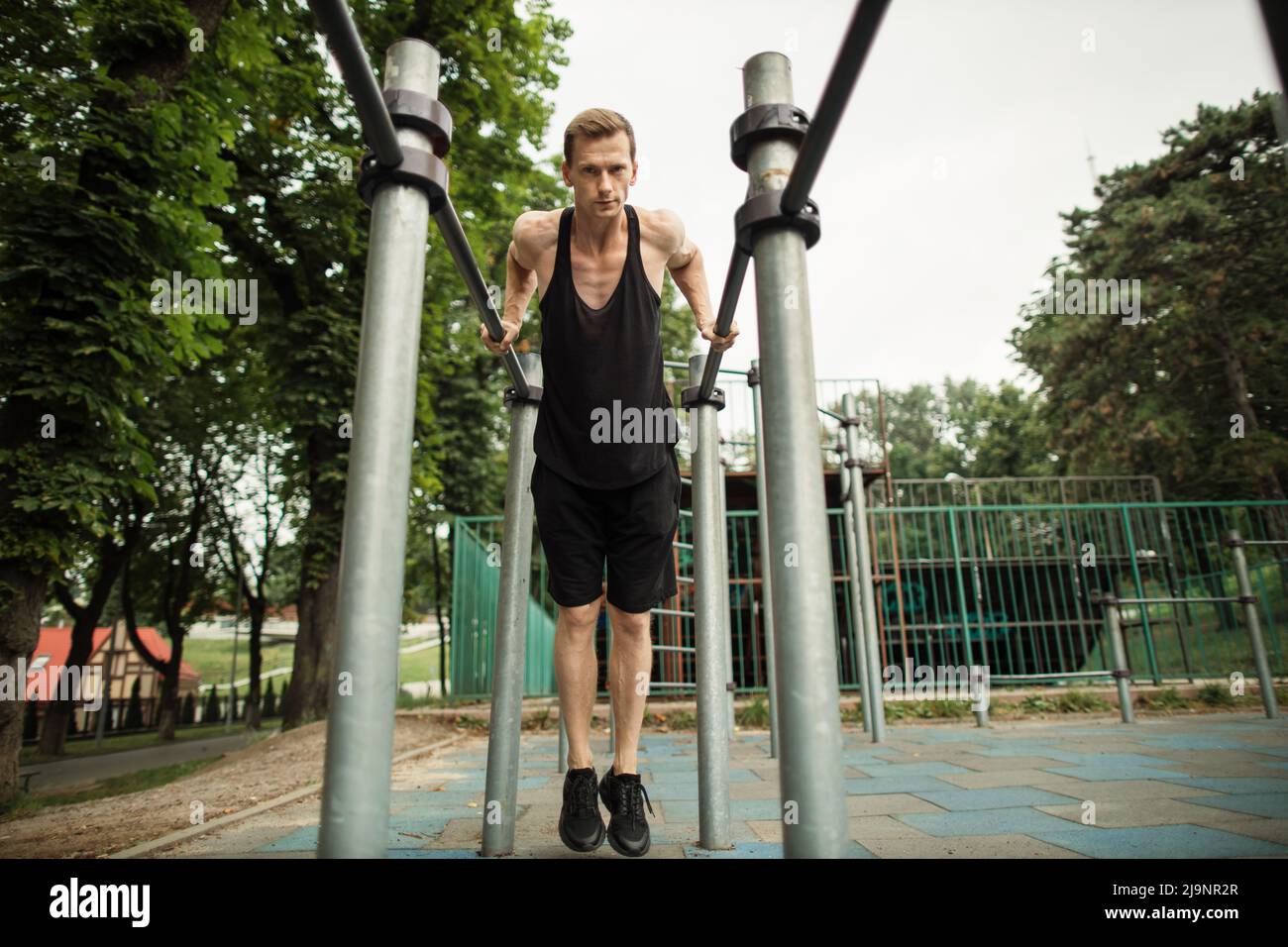 Young caucasian sporty muscular fit man doing triceps dips on parallel ...