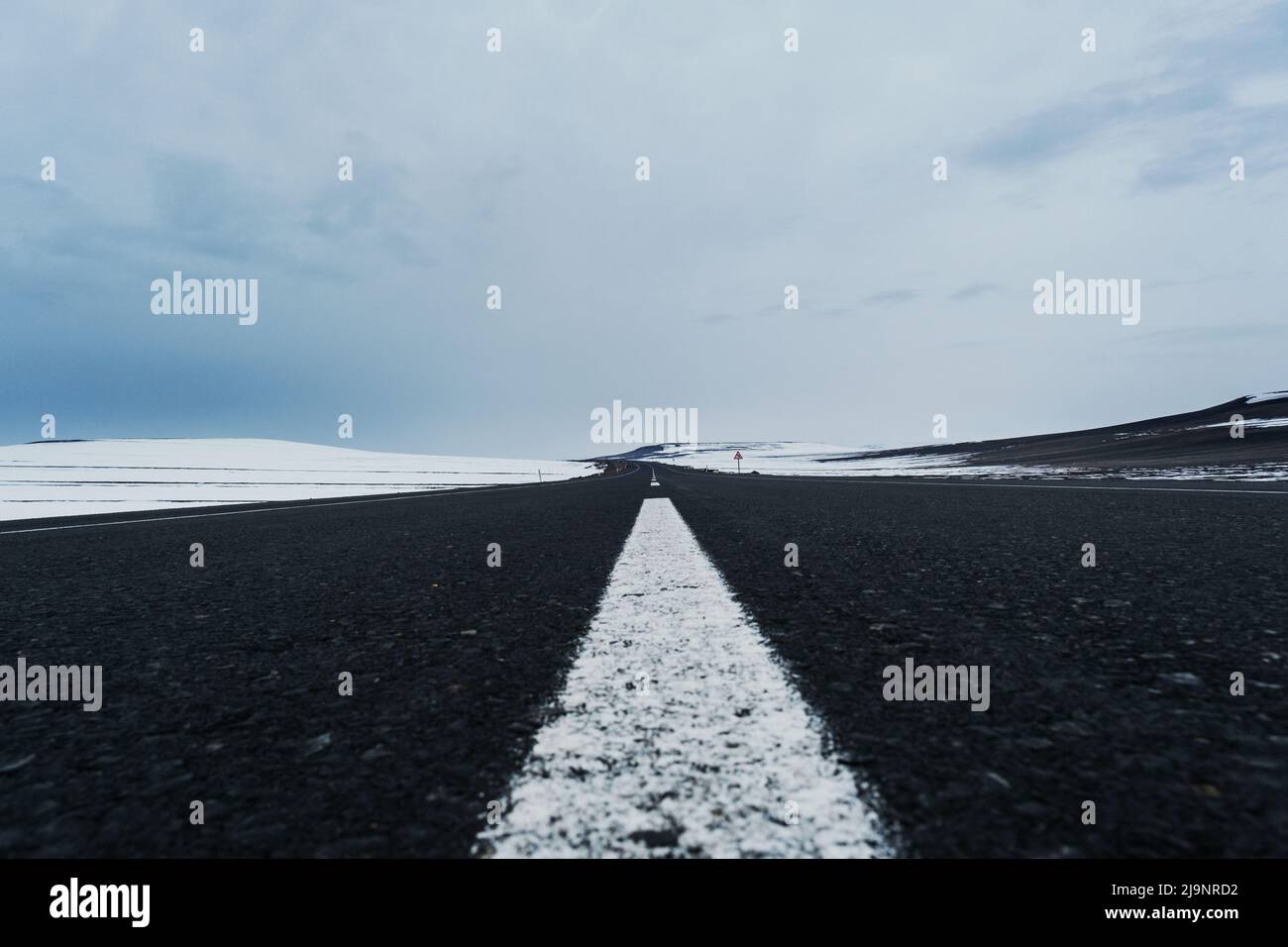 Close up View of an emtpy asphalt road with lanes and snow in winter ...