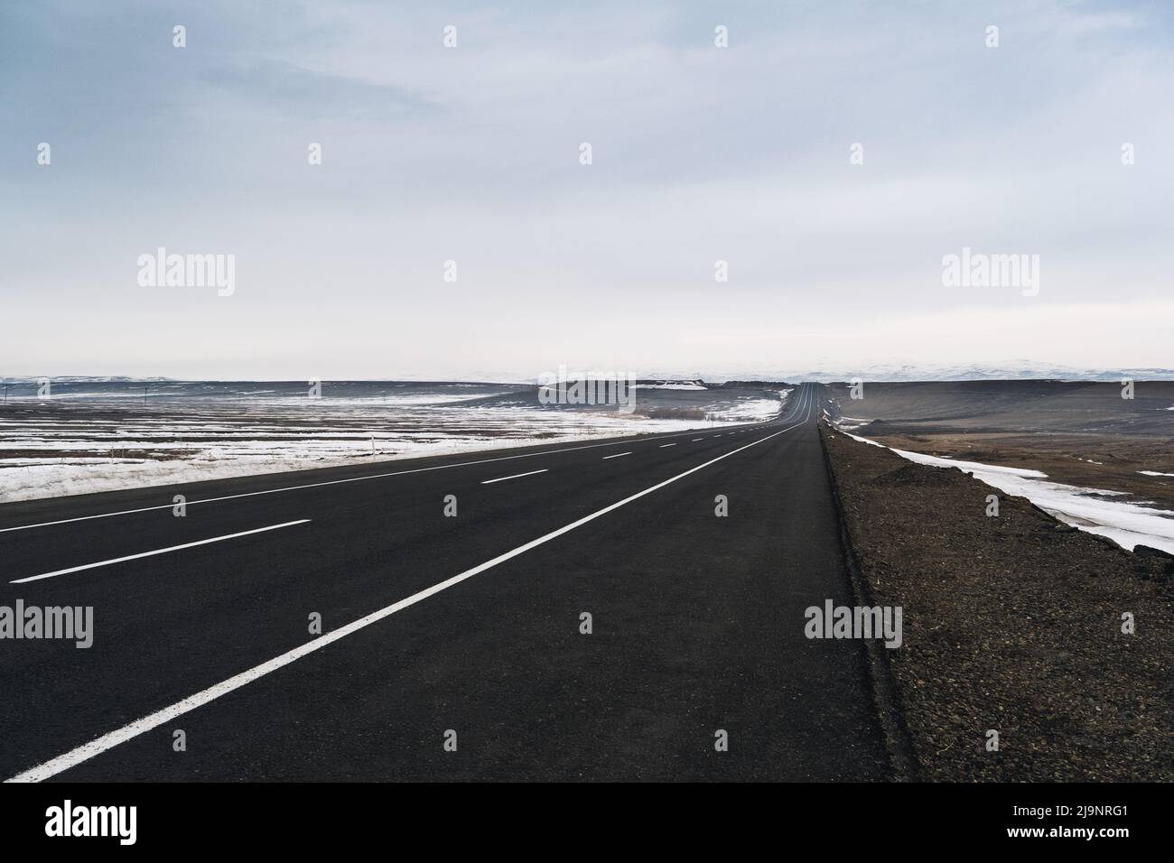 Diagonal view of an emtpy asphalt road with lanes snow and a ramp in ...