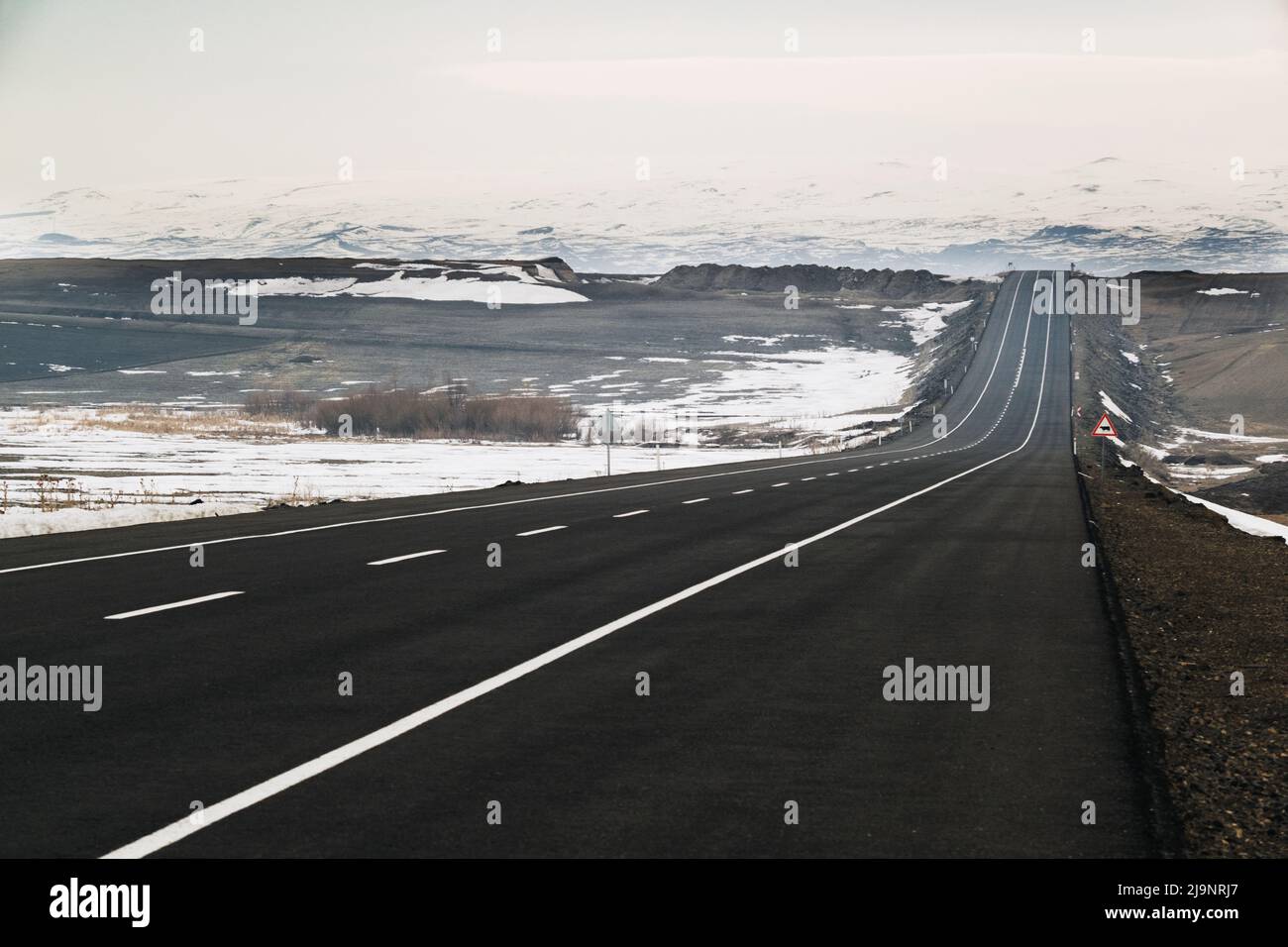 Diagonal view of an emtpy asphalt road with lanes snow and a ramp in ...