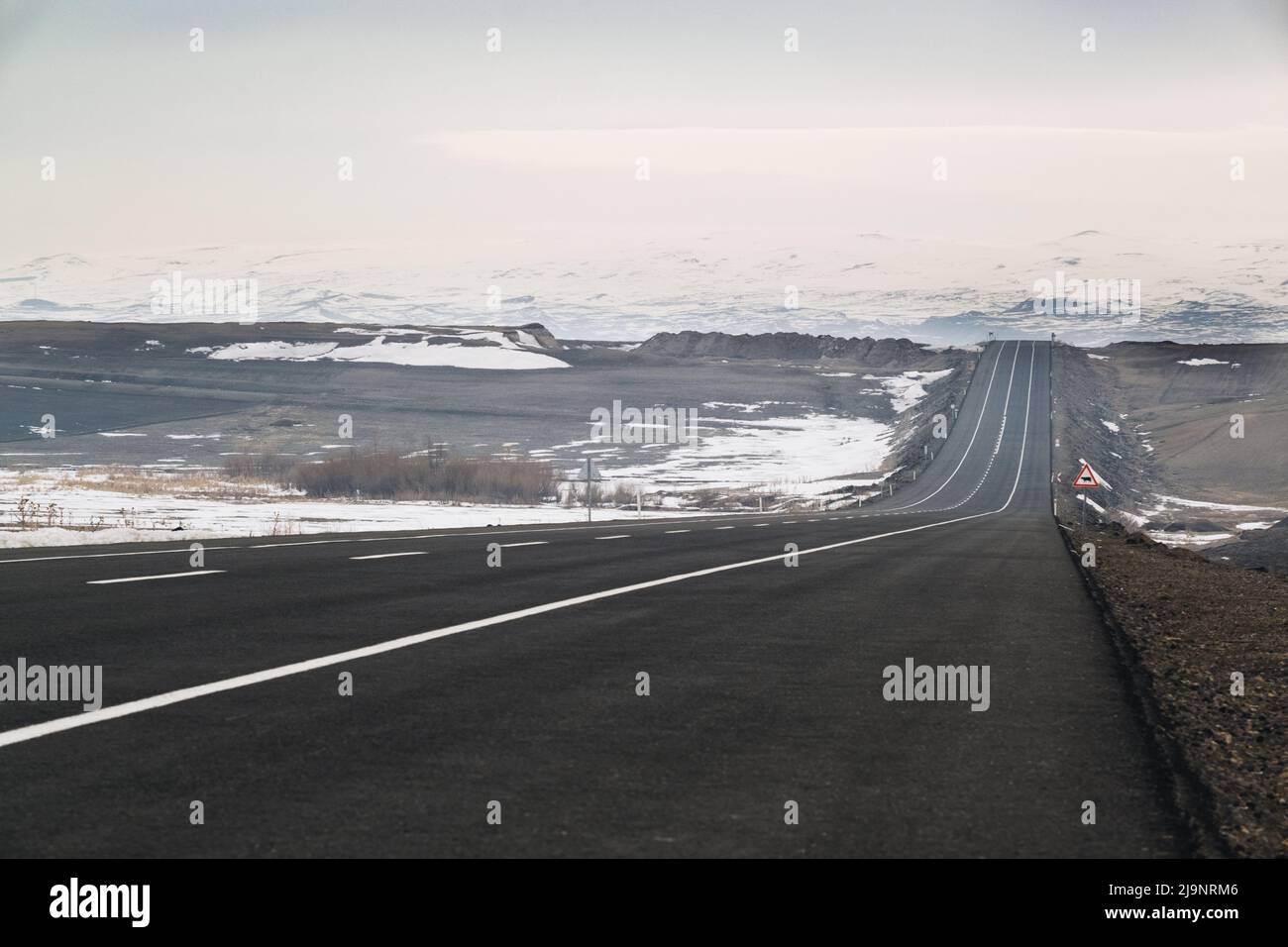 Diagonal view of an emtpy asphalt road with lanes snow and a ramp in ...