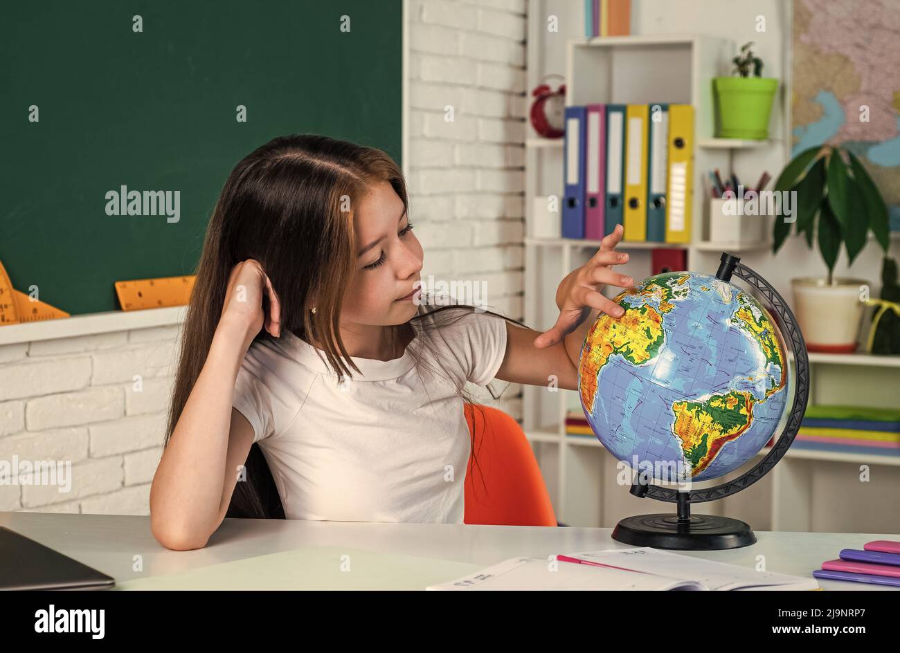 cheerful kid girl with globe at school lesson, geography Stock Photo ...