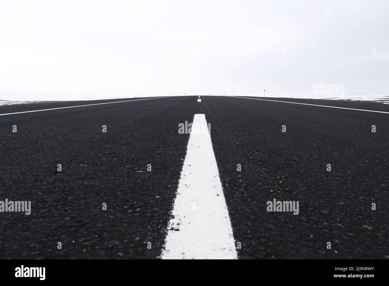 Close up View of an emtpy asphalt road with lanes and snow in winter ...