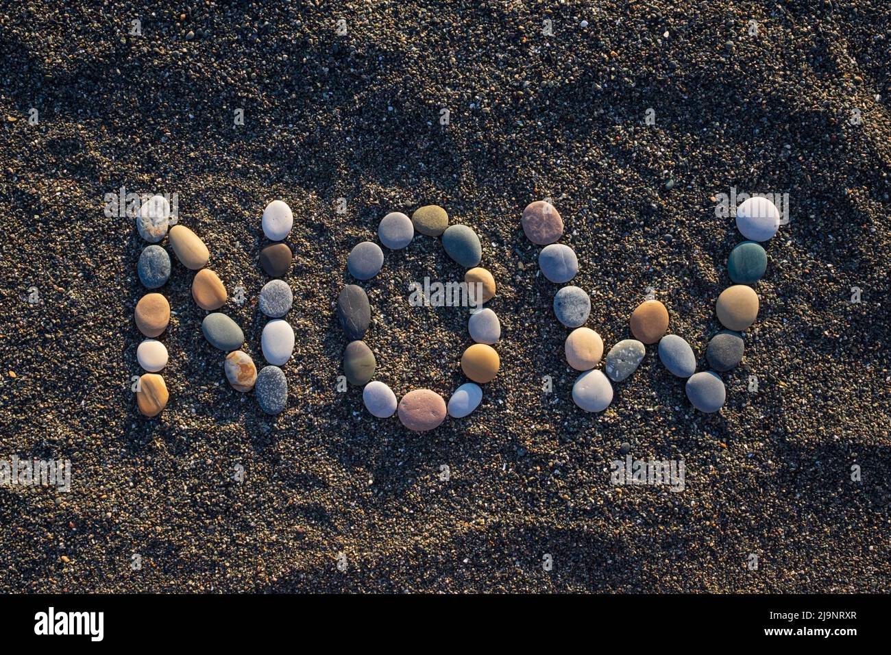 Word now made form stones on sandy beach Stock Photo - Alamy