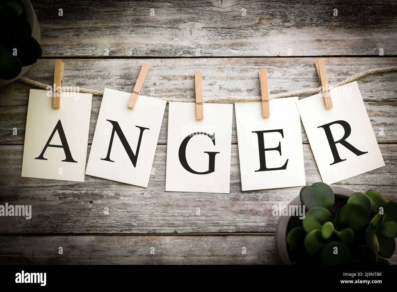 A set of printed cards spelling the word ANGER on an aged wooden ...