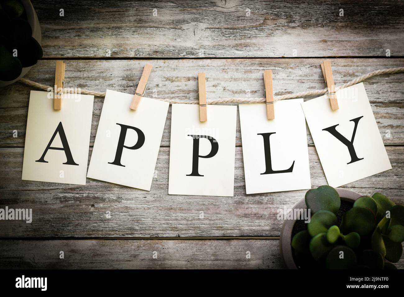 A set of printed cards spelling the word APPLY on an aged wooden ...