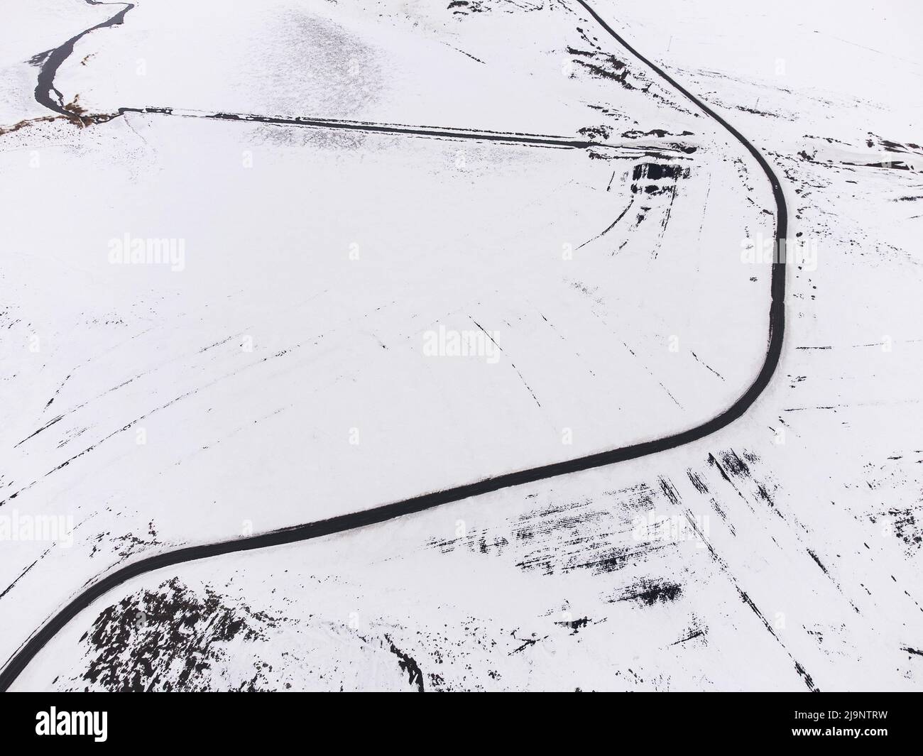 Aerial top view of a S shaped road with one lane and snow in winter ...