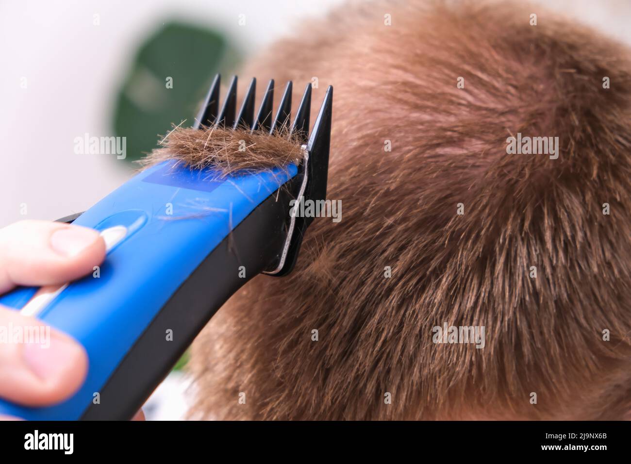 A man cuts his hair with a clipper. Cutting a short hairstyle at home ...