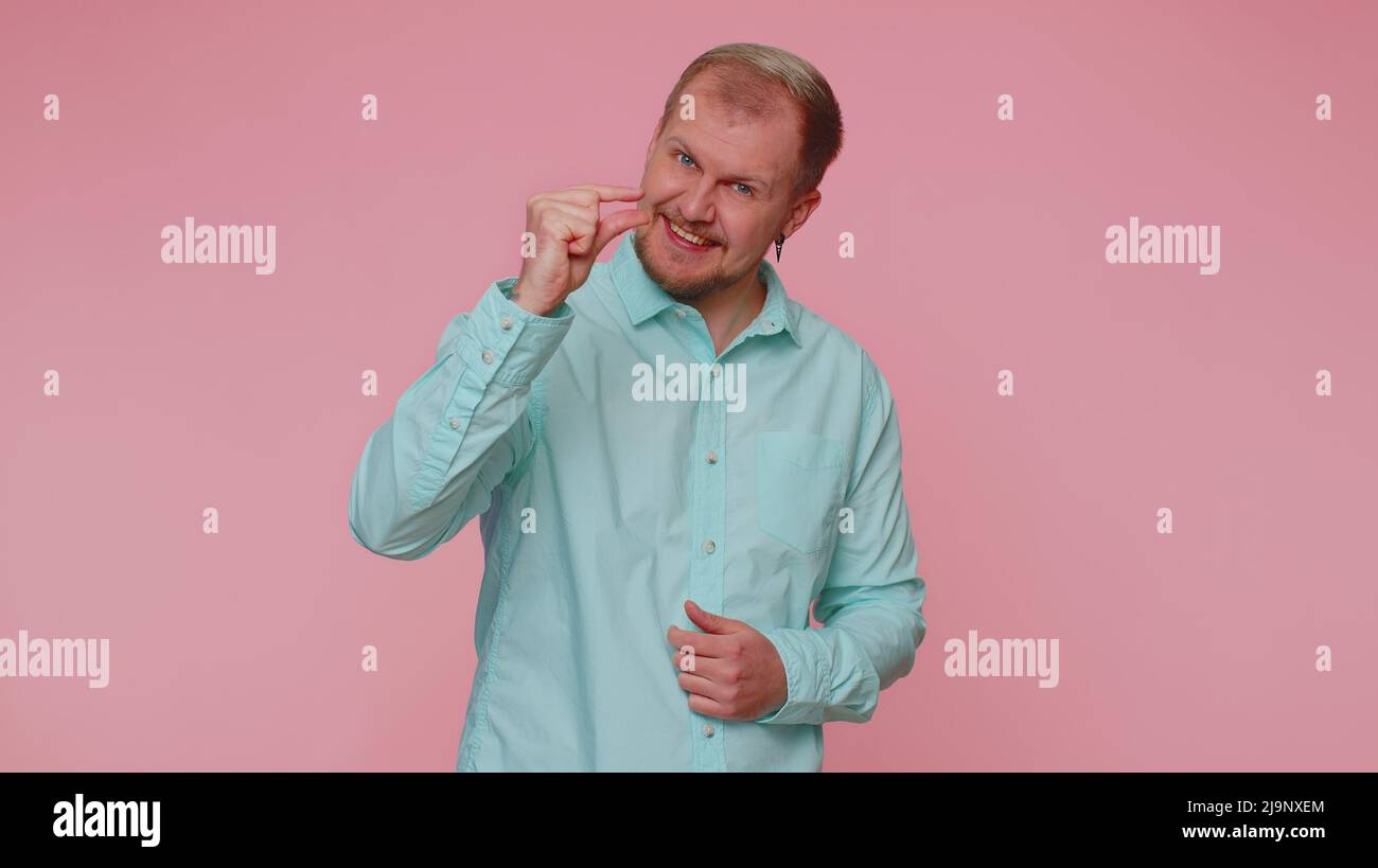 Man showing a little bit gesture with sceptic smile, showing minimum ... Man showing a little bit gesture with sceptic smile, showing minimum ...