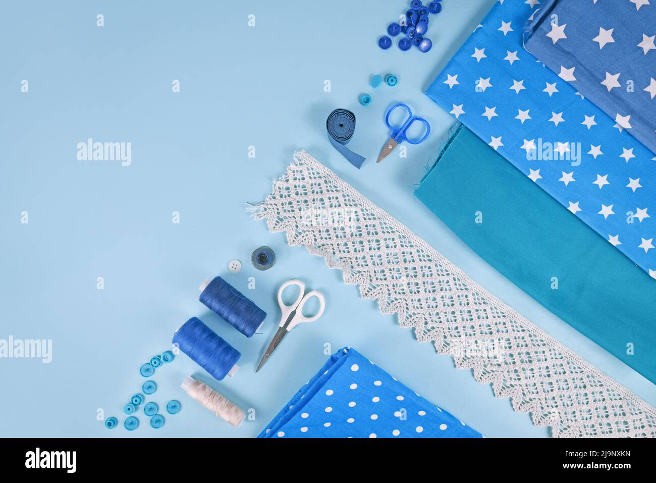 Sewing flat lay with various tools like fabric, scissors, spools and ...