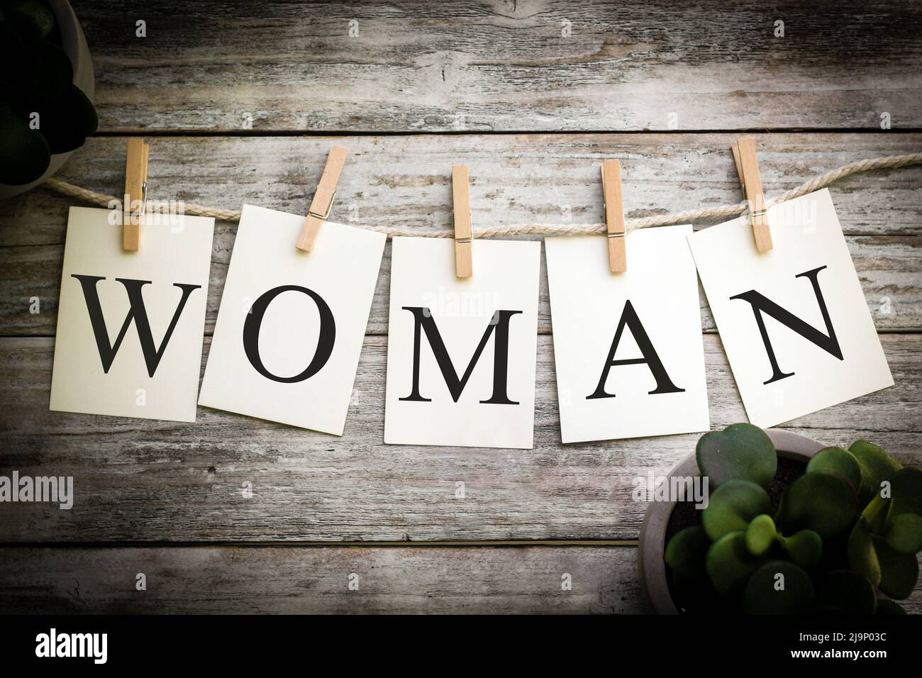 A set of printed cards spelling the word WOMAN on an aged wooden ...