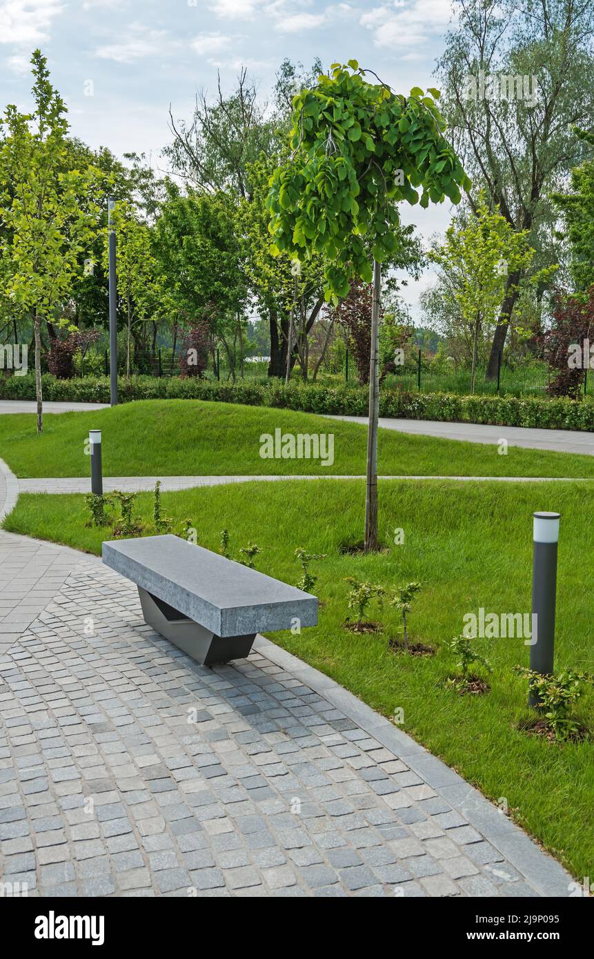 Rectangular hewn stone granite park bench on background of lawn with ...