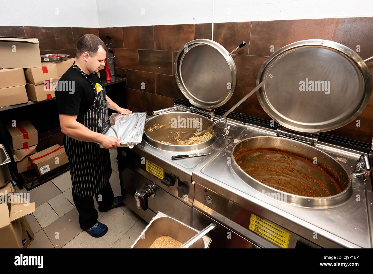 A volunteer at a World Central Kitchen location prepares food, (meals ...