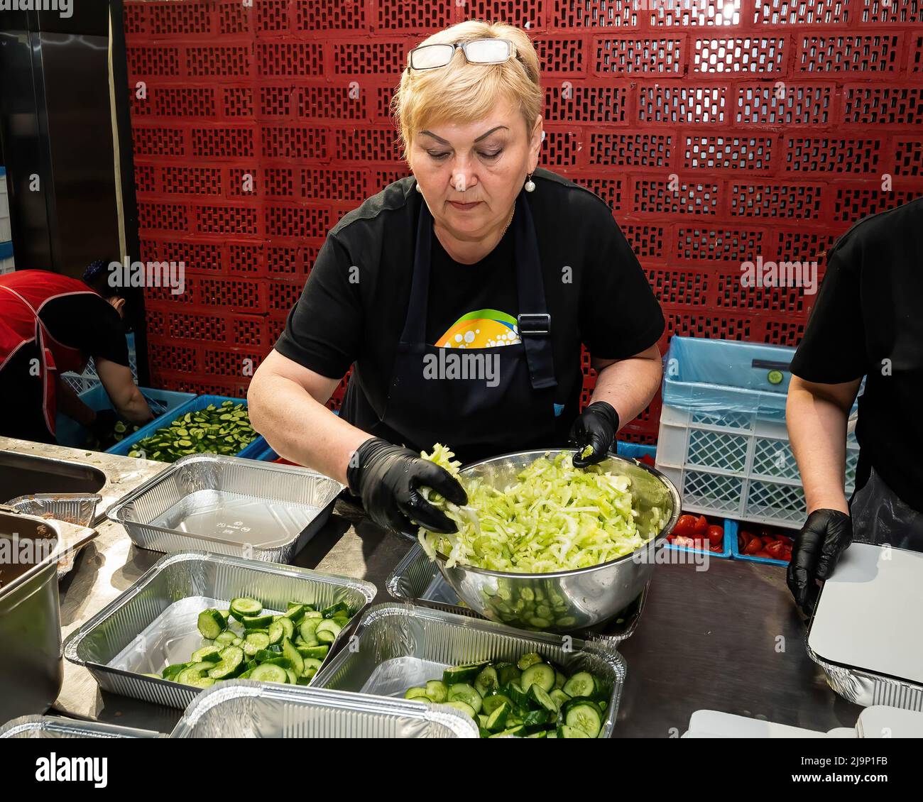 A volunteer at a World Central Kitchen location prepares food, (meals ...