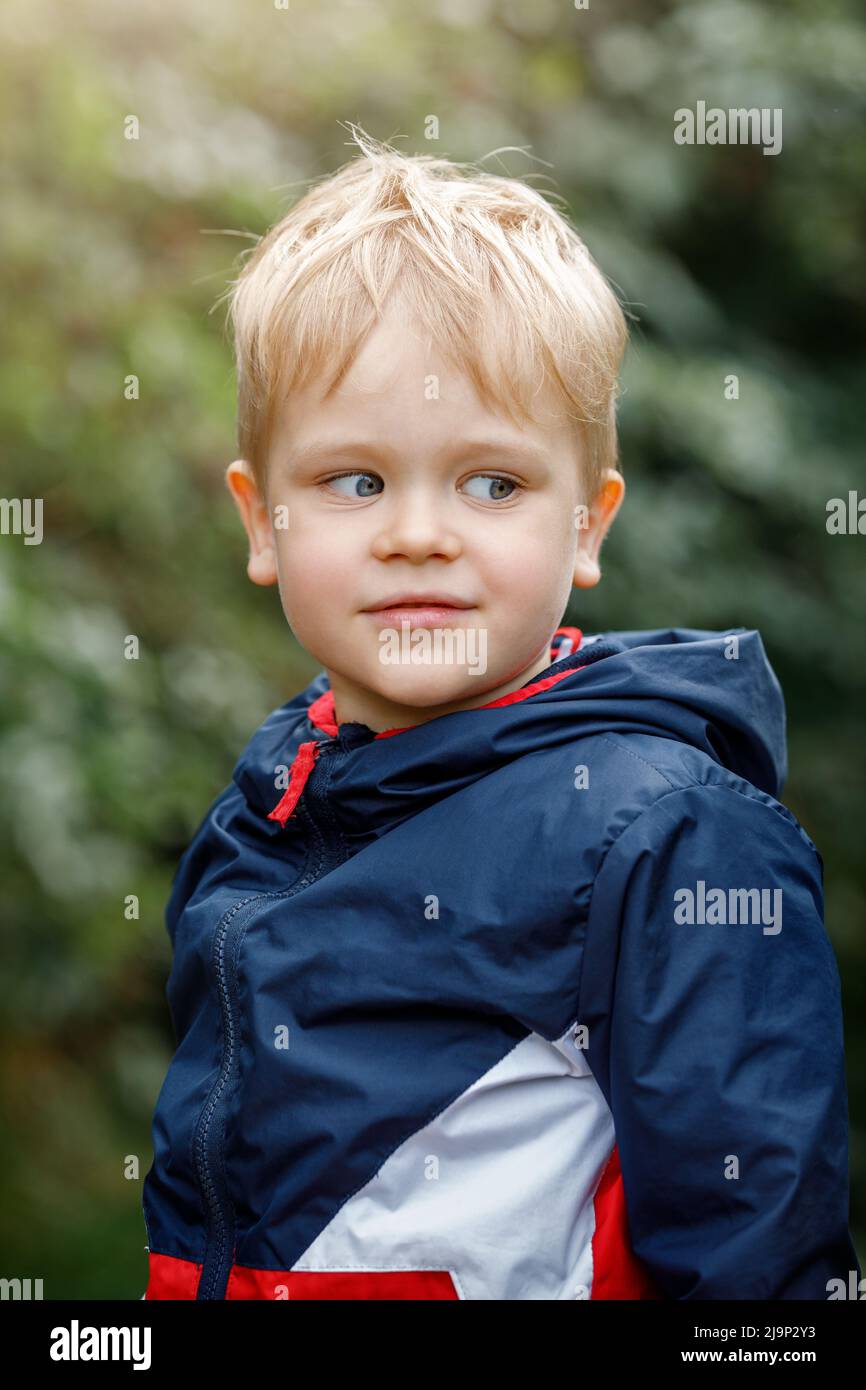 A portrait of a cheerful little, cute boy up close to nature against a ...